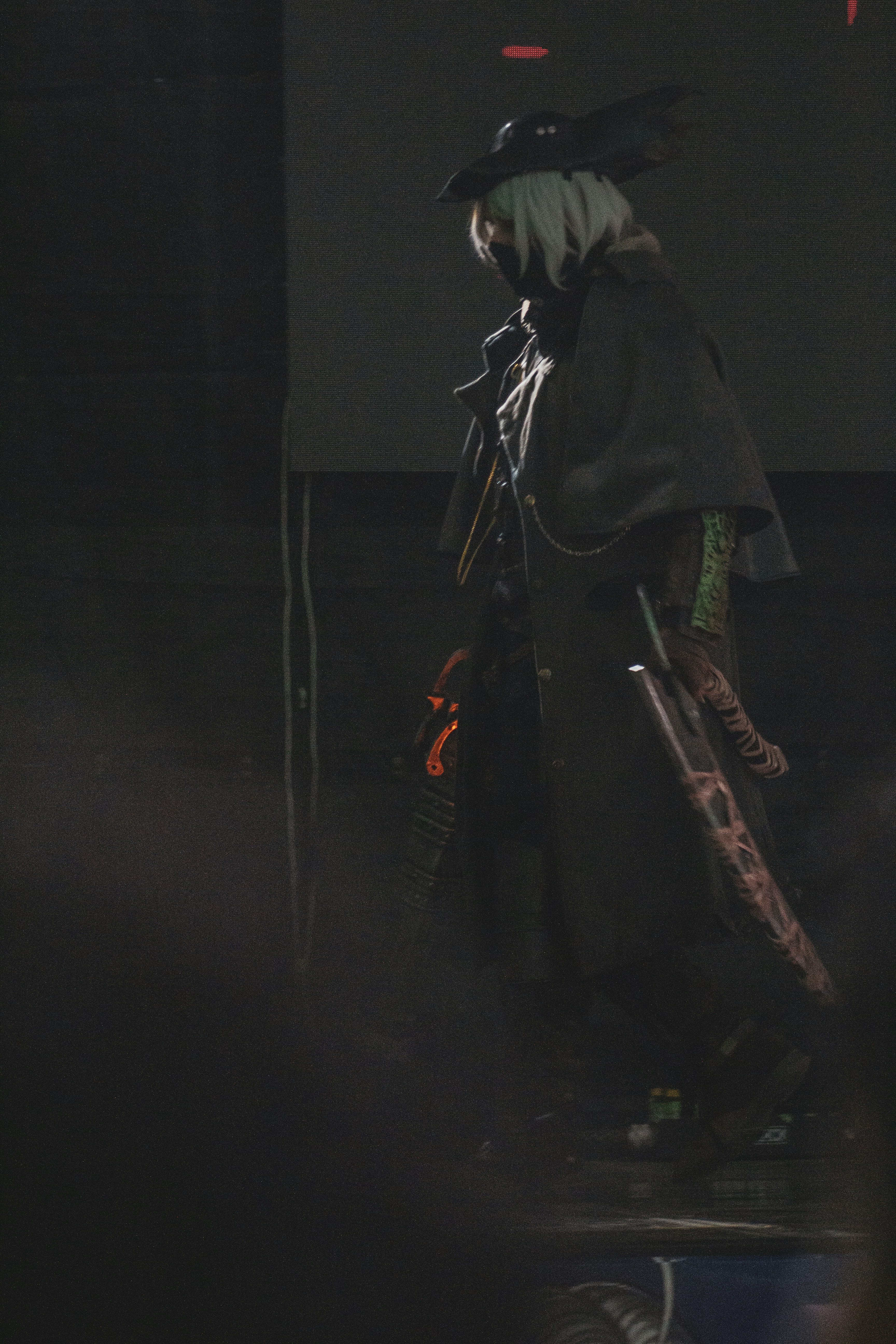 Masked wanderer with chrome blade under dim stage light
