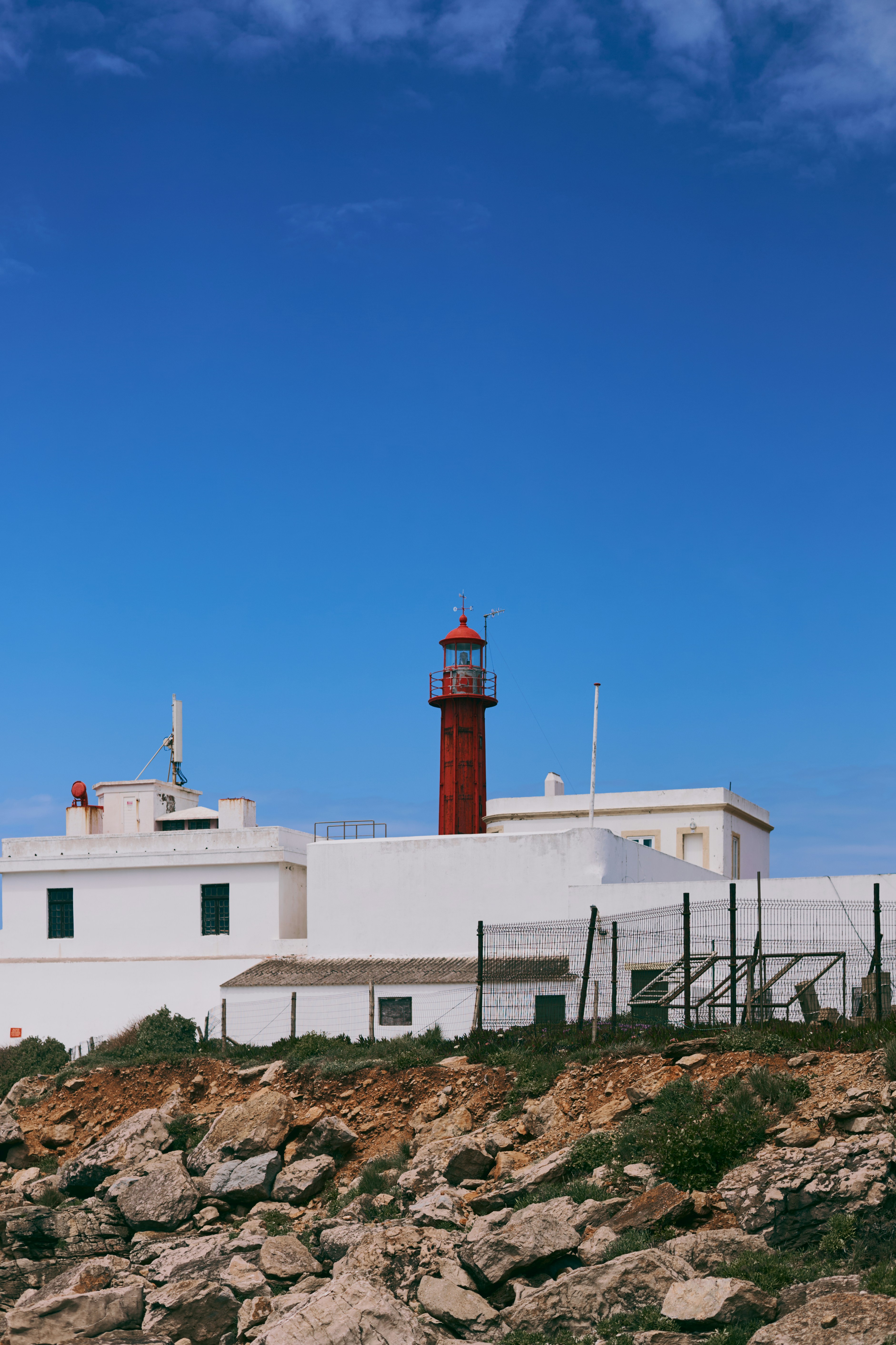 Red Beacon Over White Cottages Against a Clear Coastal Sky