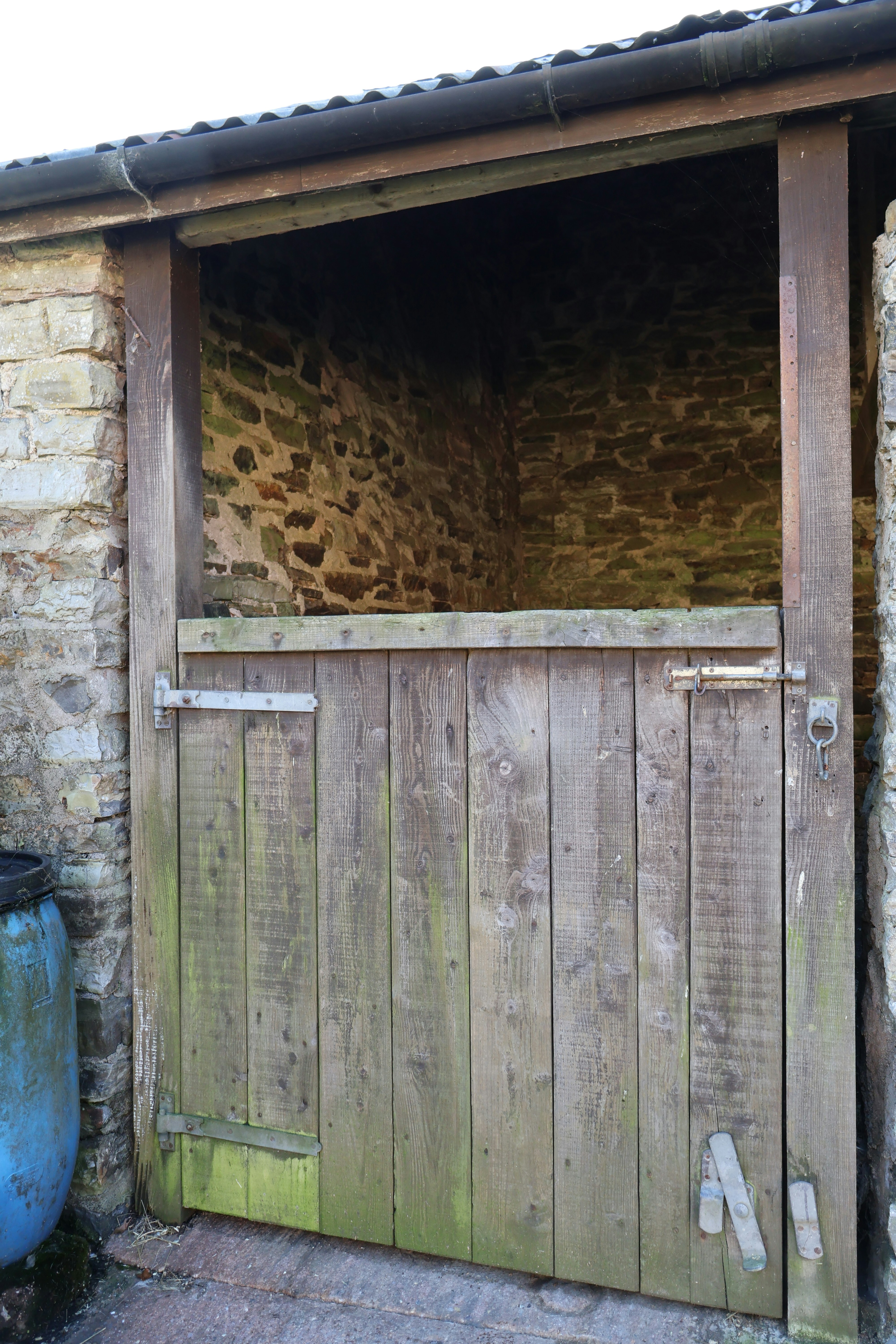 Weathered Stable: Mossy Timber Gate to a Stone Barn