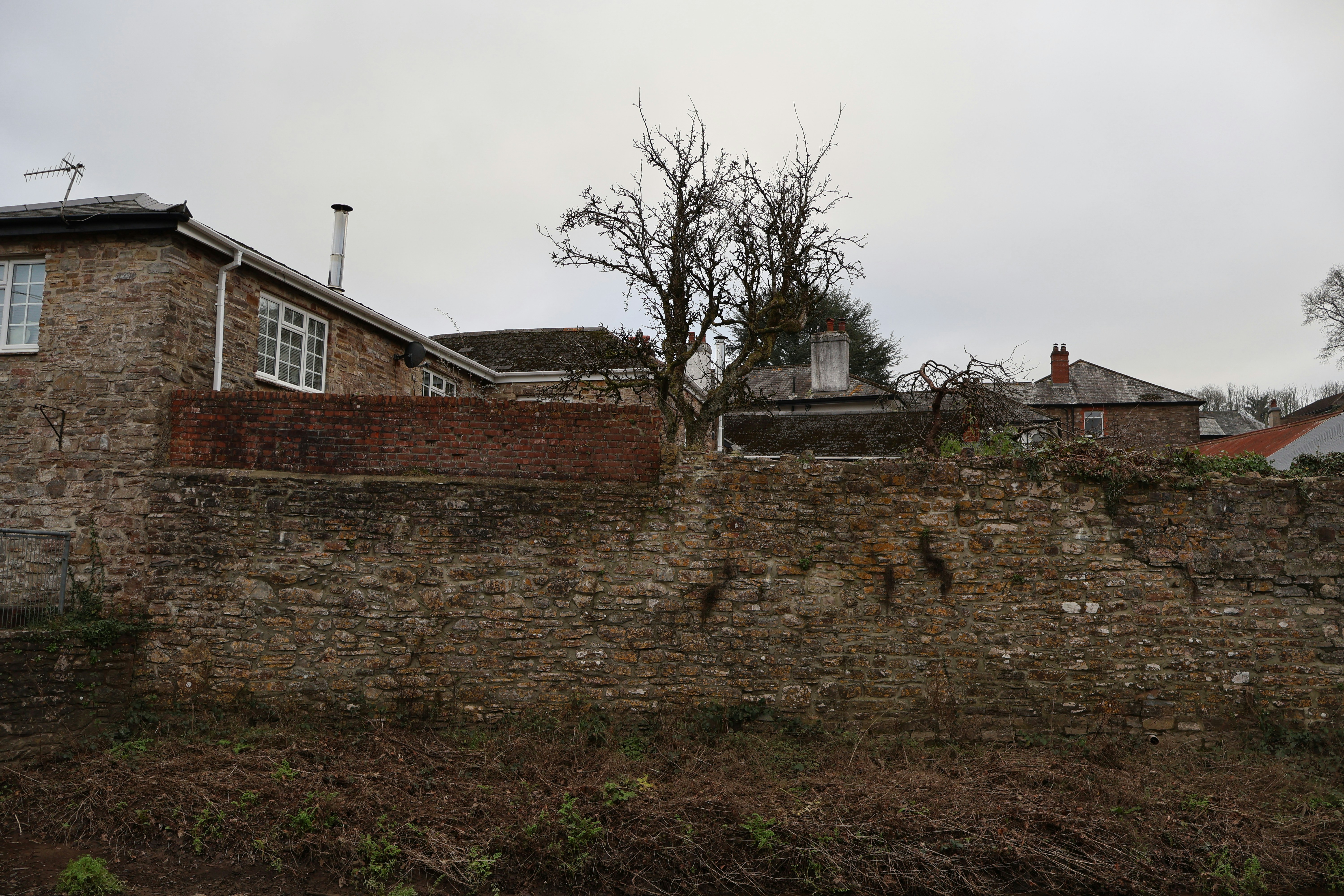 Weathered Stones and Quiet Sky: A Suburban Wall Framed by Distant Homes