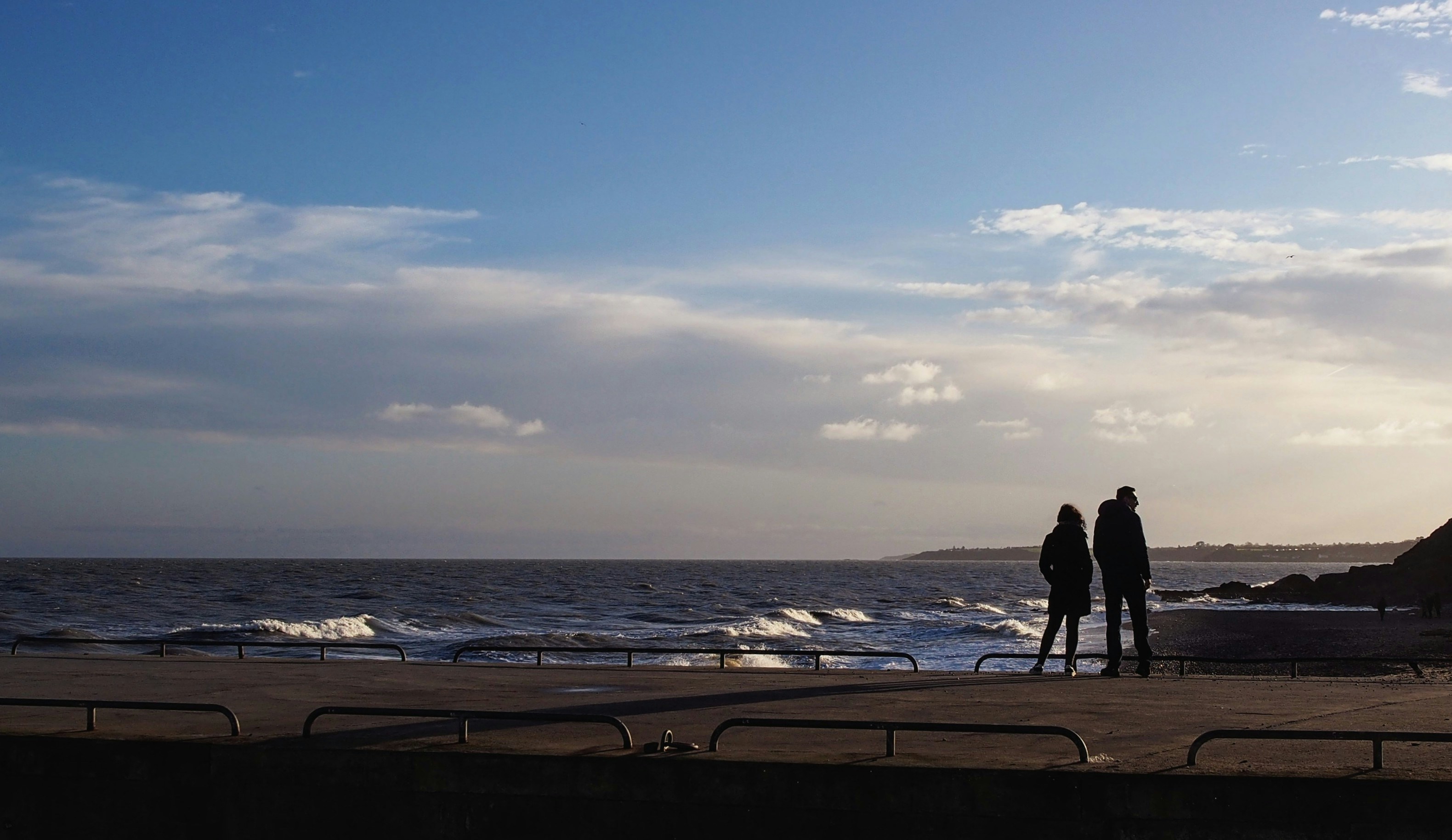 Silhouetted Duo by the Sea at Sunset