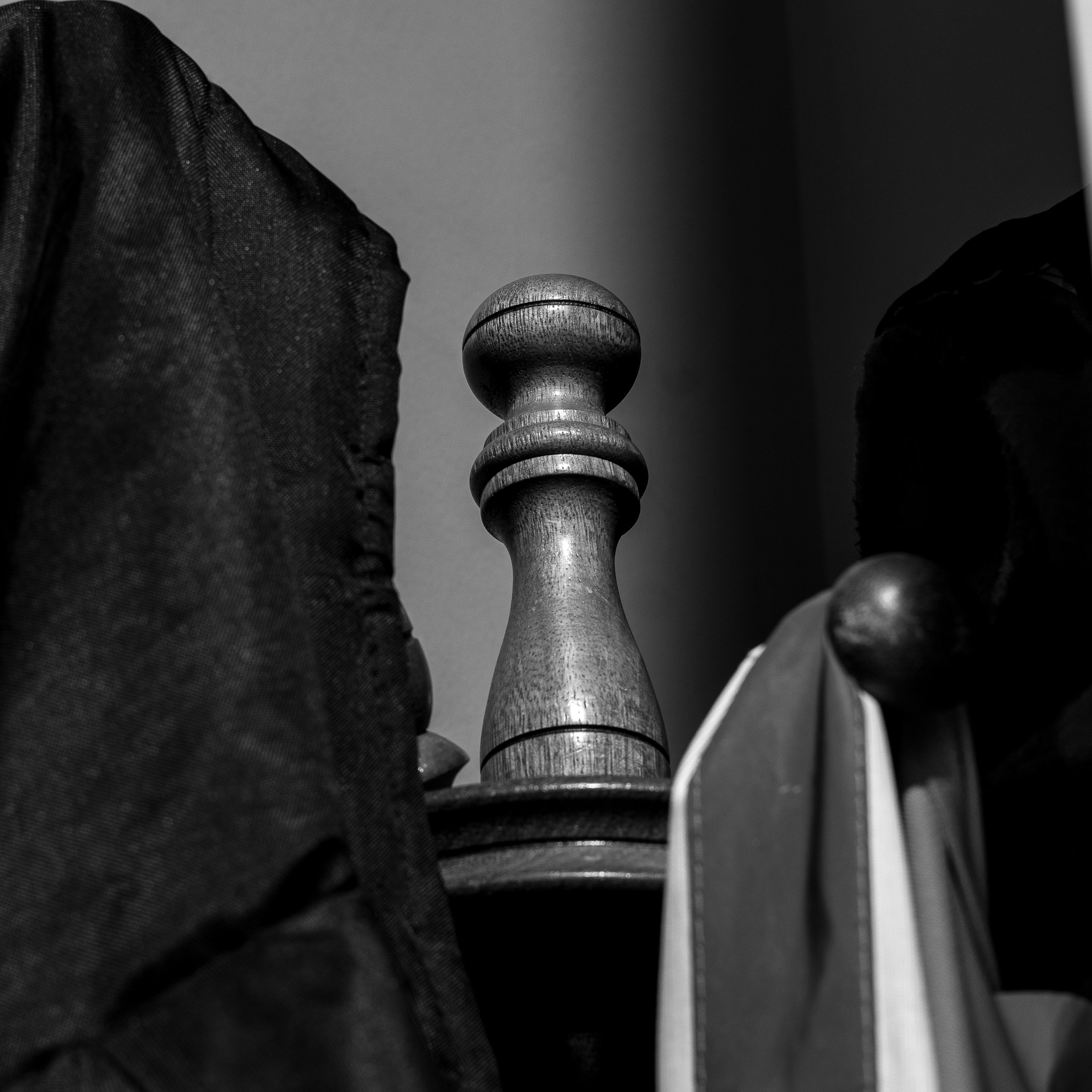 The Silent King: A Chess Pawn Framed Between Fabric and Shadow