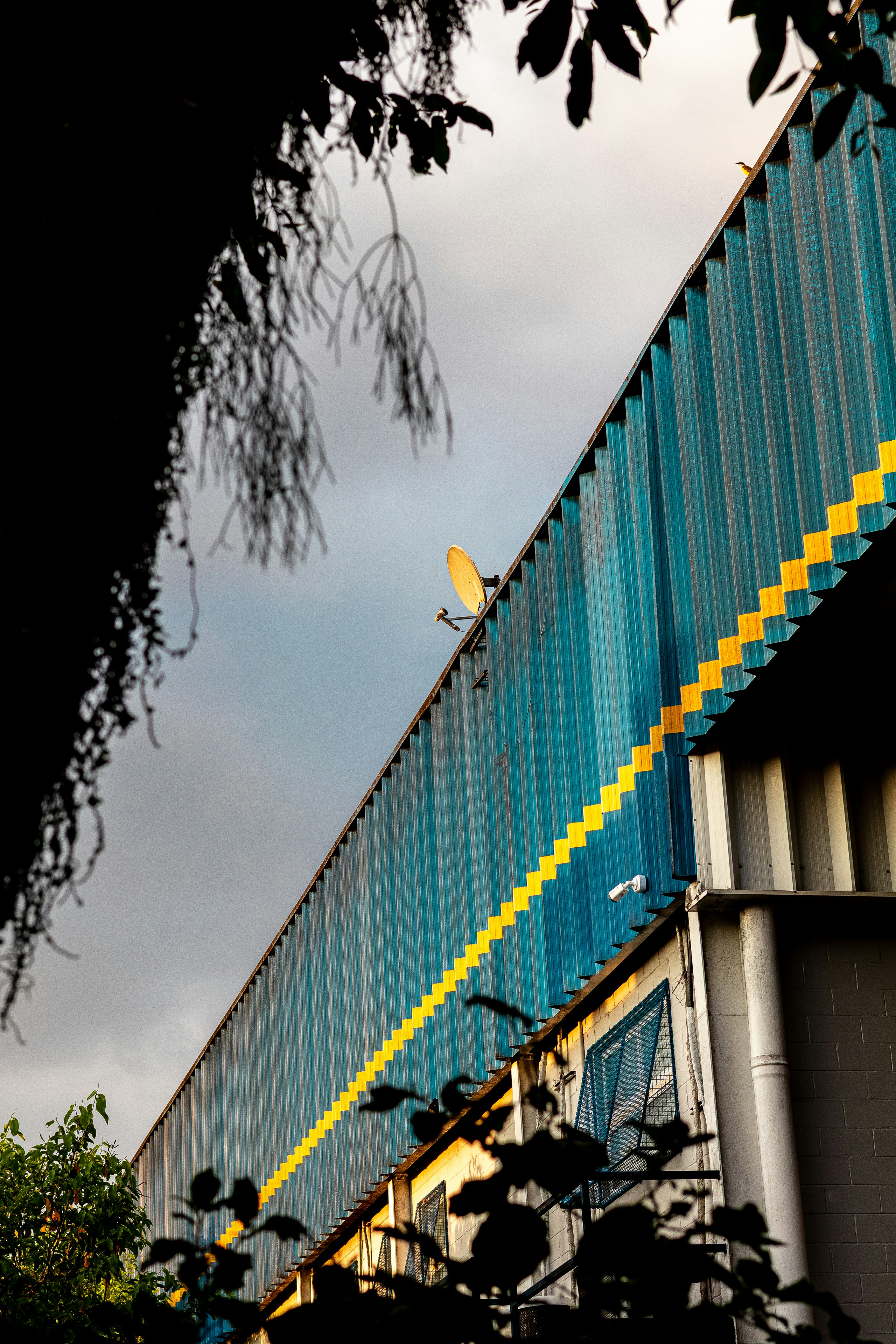 Blue corrugated building with yellow stripe and satellite dish photo ...