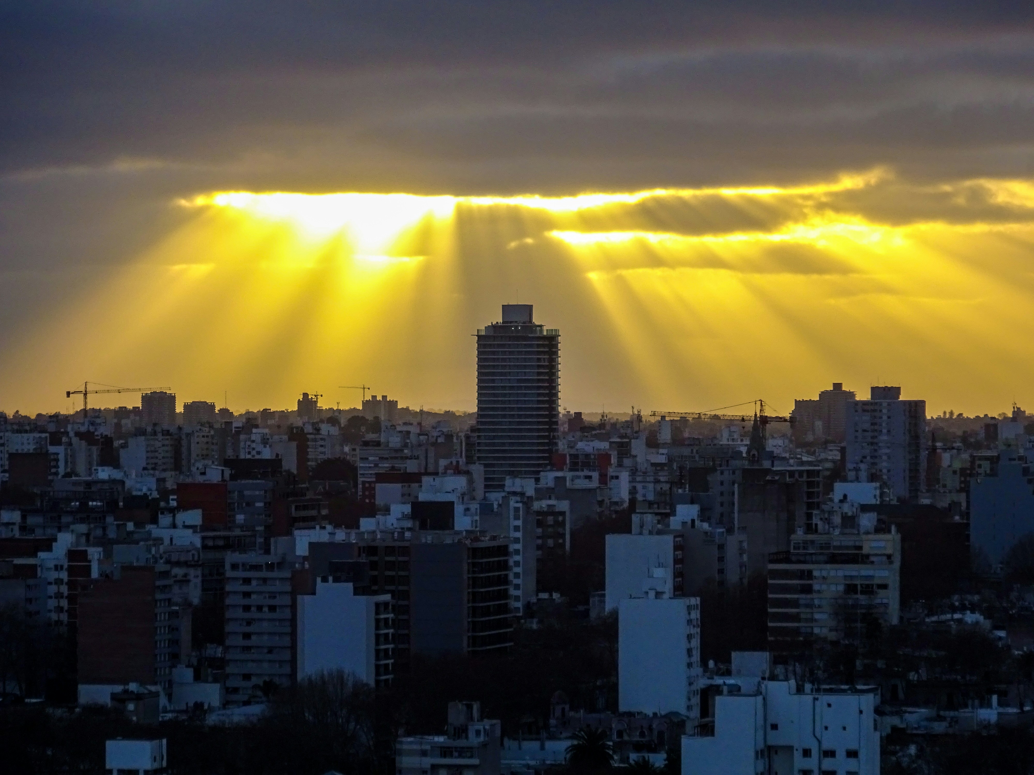 Rays of gold over a cityscape: sunrise slicing through the skyline