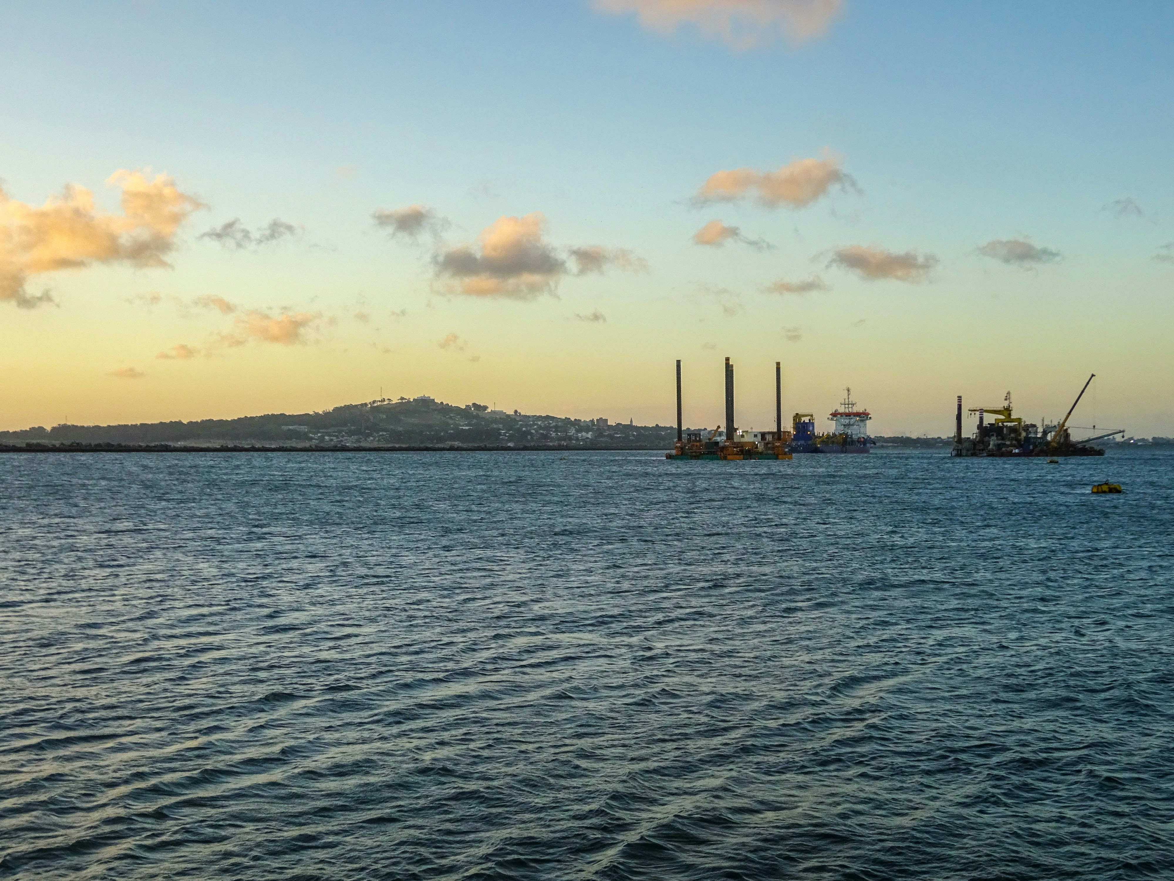 Distant Harbor at Dusk: Quiet Industrial Silhouette Across Calm Seas