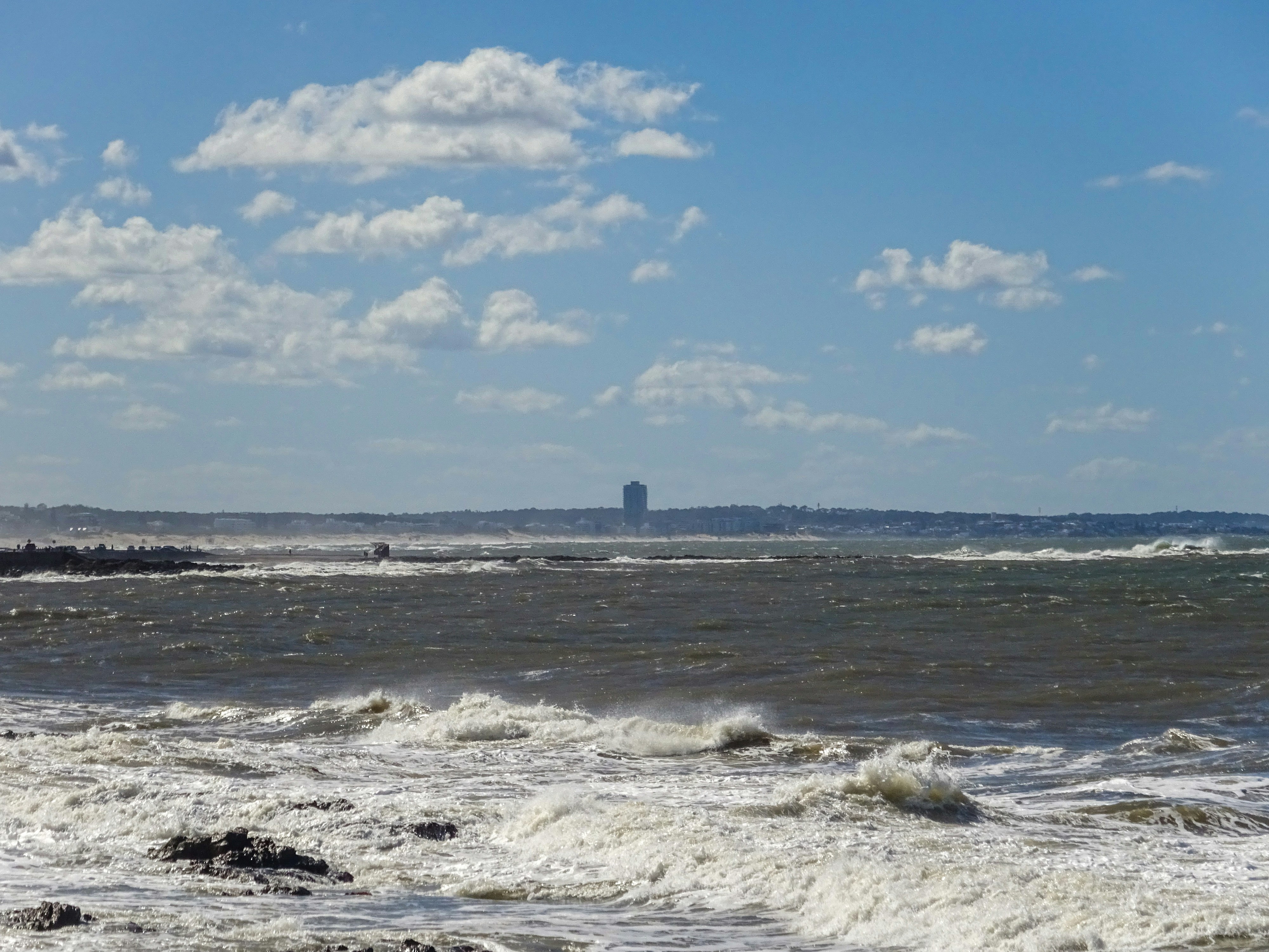 Distant City Silhouette Above Rolling Coastal Waves