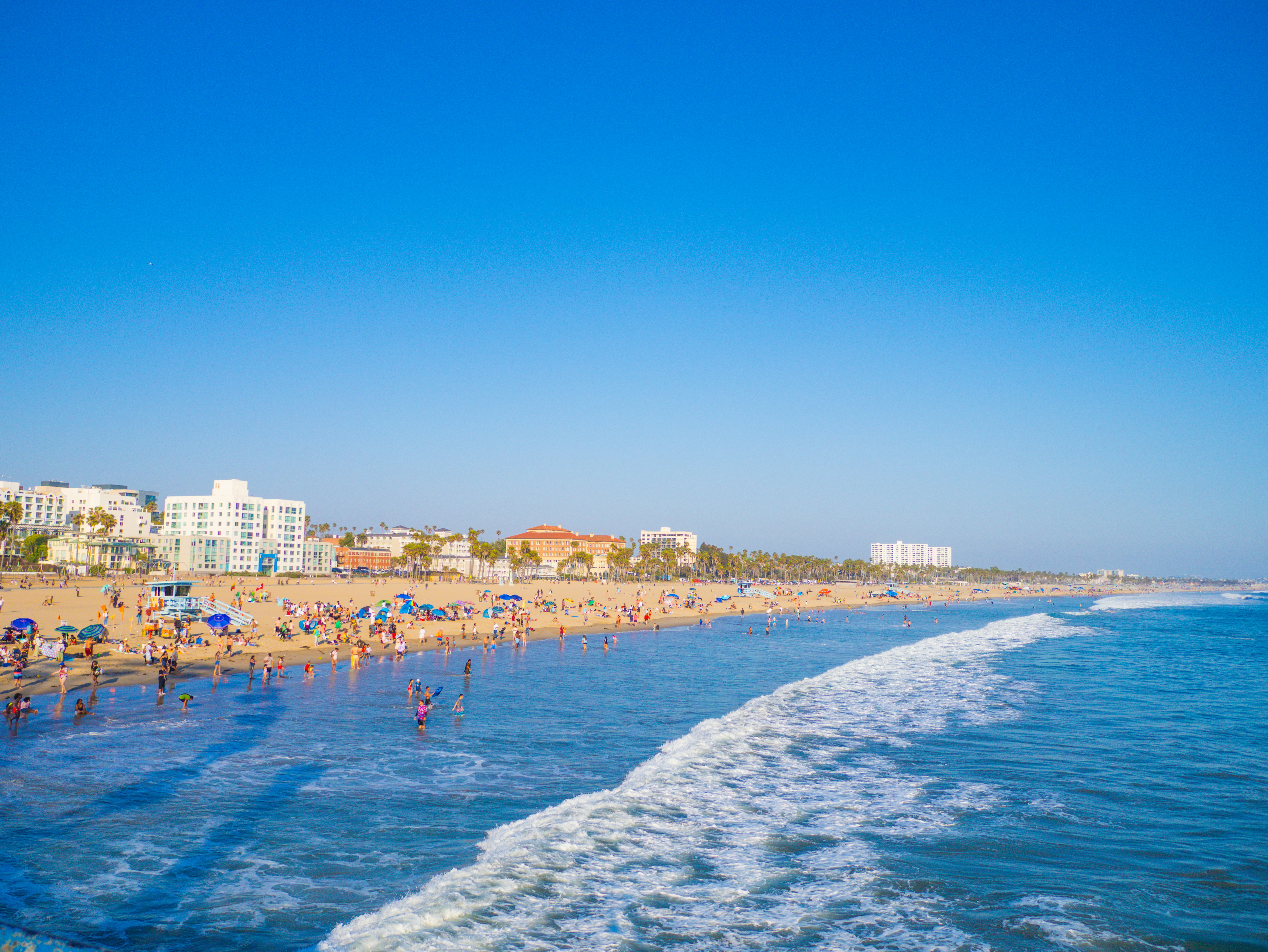 Sunlit Strand: Distant Row of Beachfront Buildings Fringed by Gentle Surf