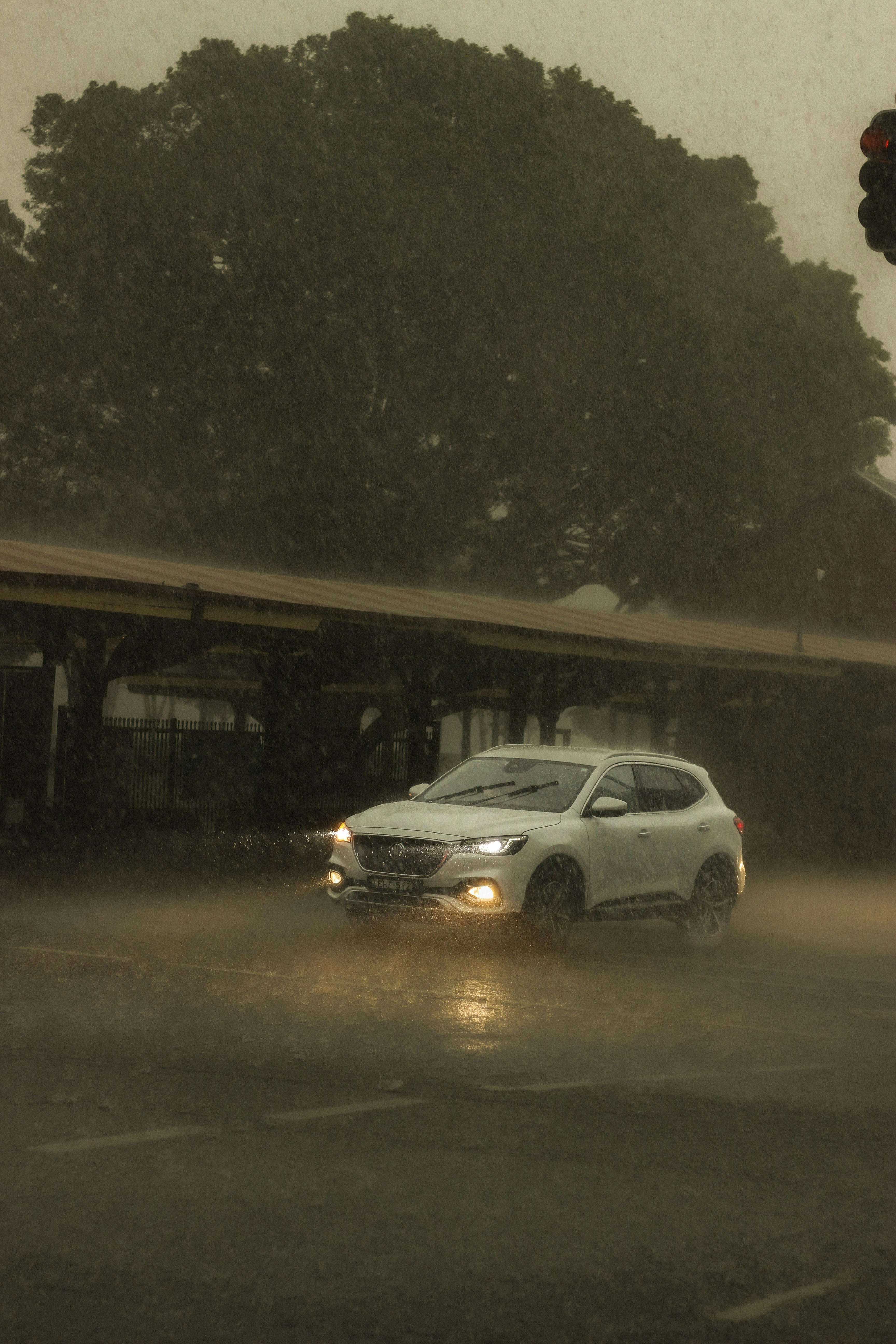 White SUV Navigates a Downpour at an Urban Intersection