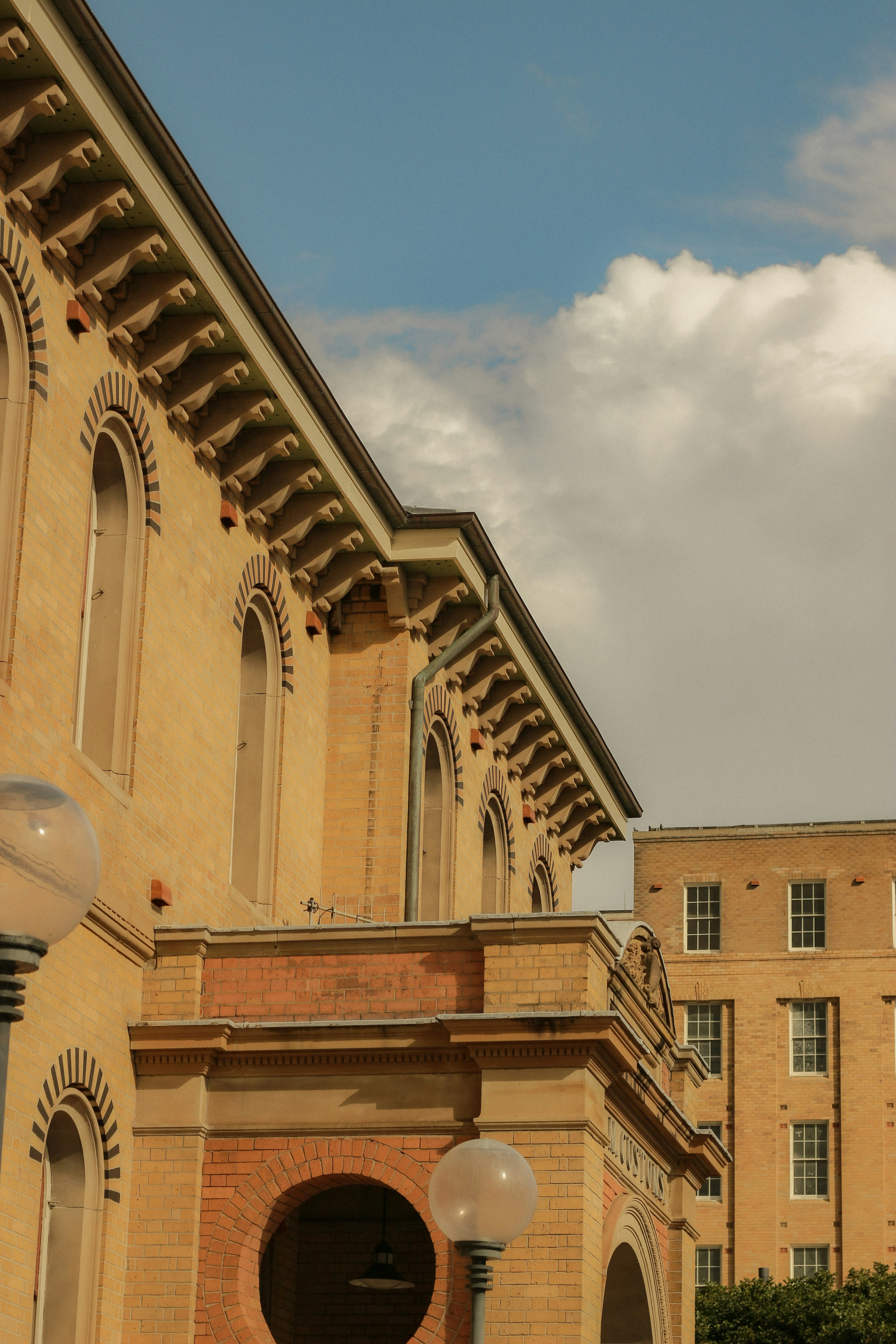 Yellow brick building with arched windows and lamps photo – Free ...