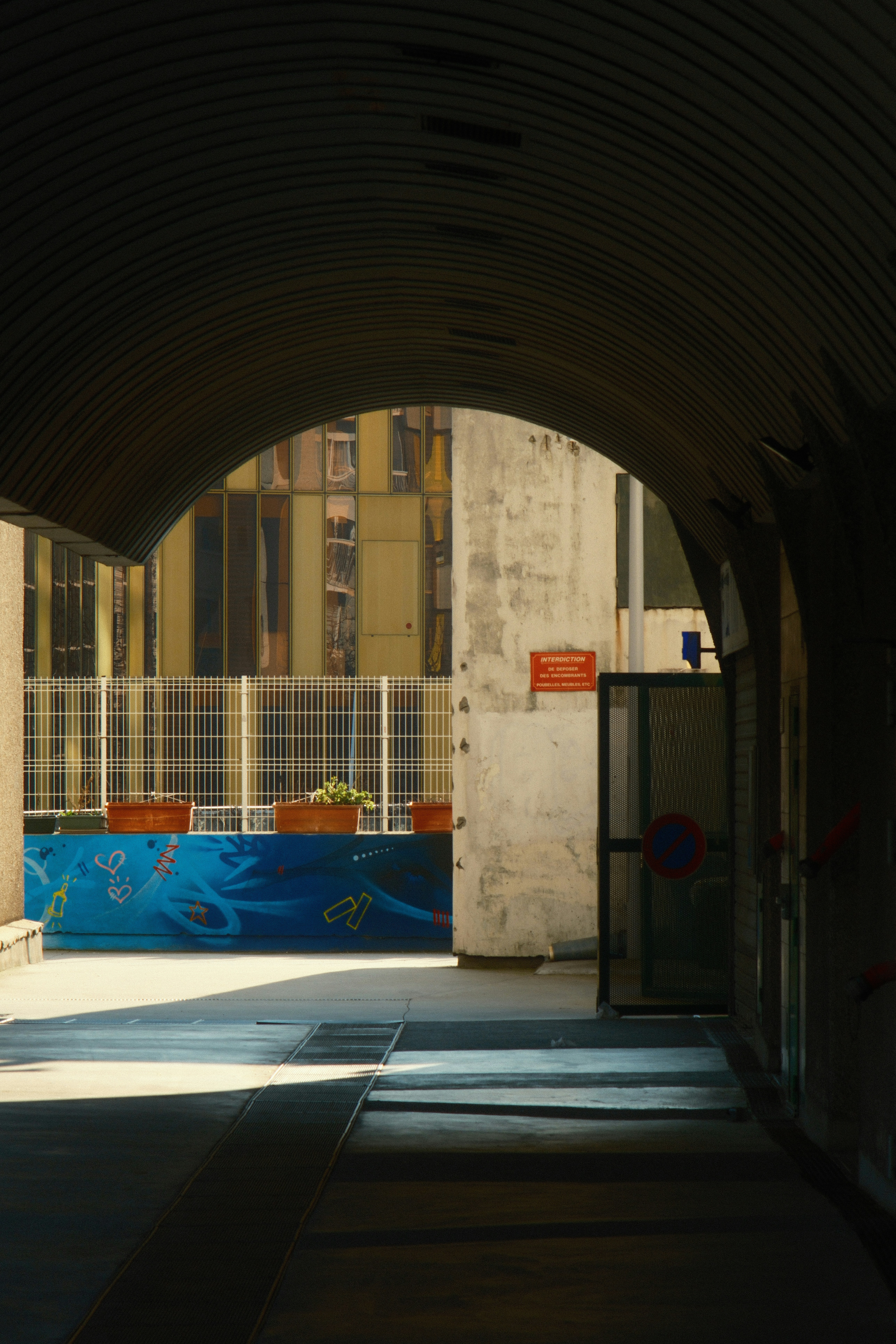 Sunlit Archway: Quiet Corridor to the Street Beyond the Fence