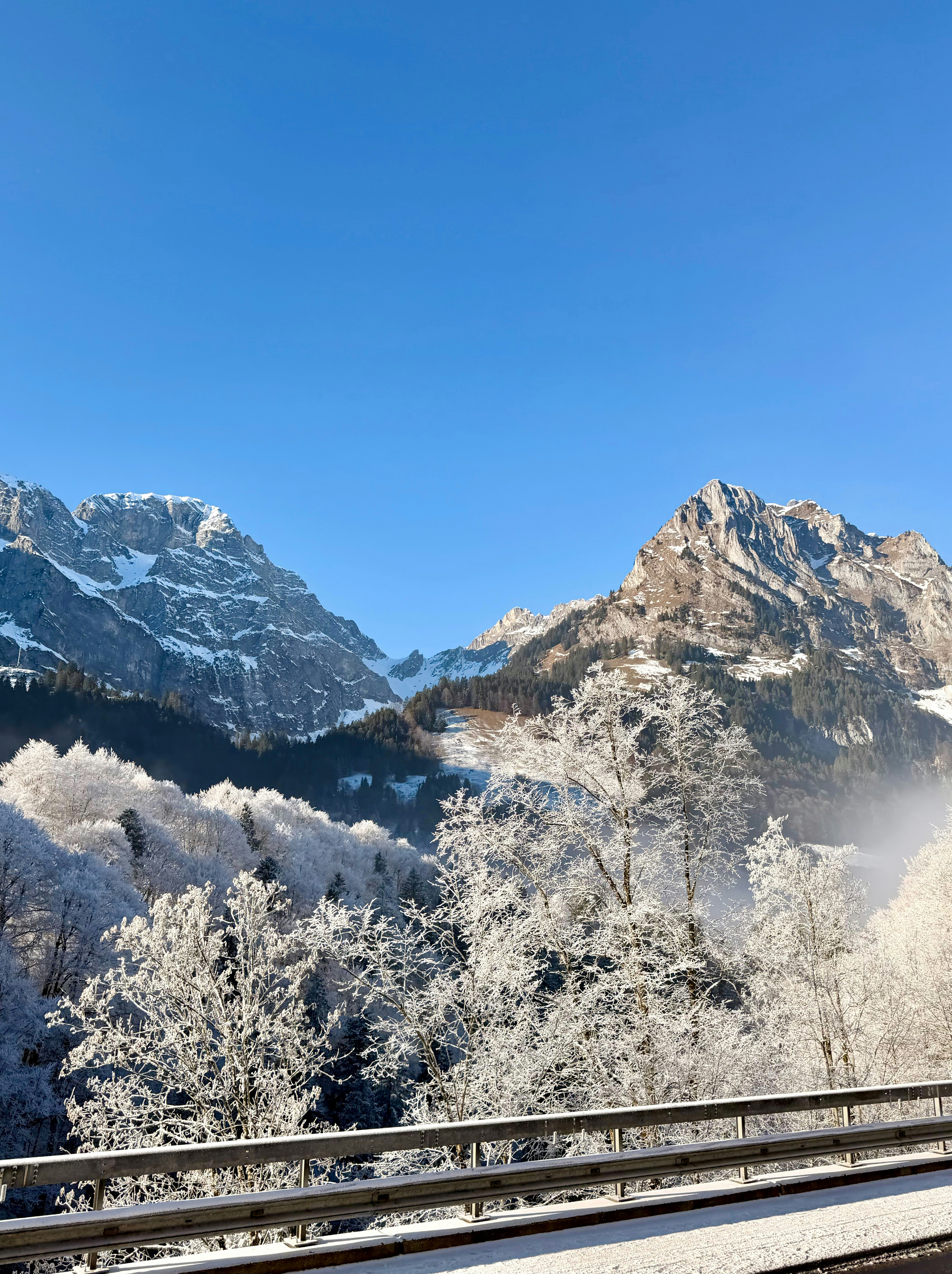 Snow-kissed Peaks Under a Pristine Blue Sky by the Guarded Road