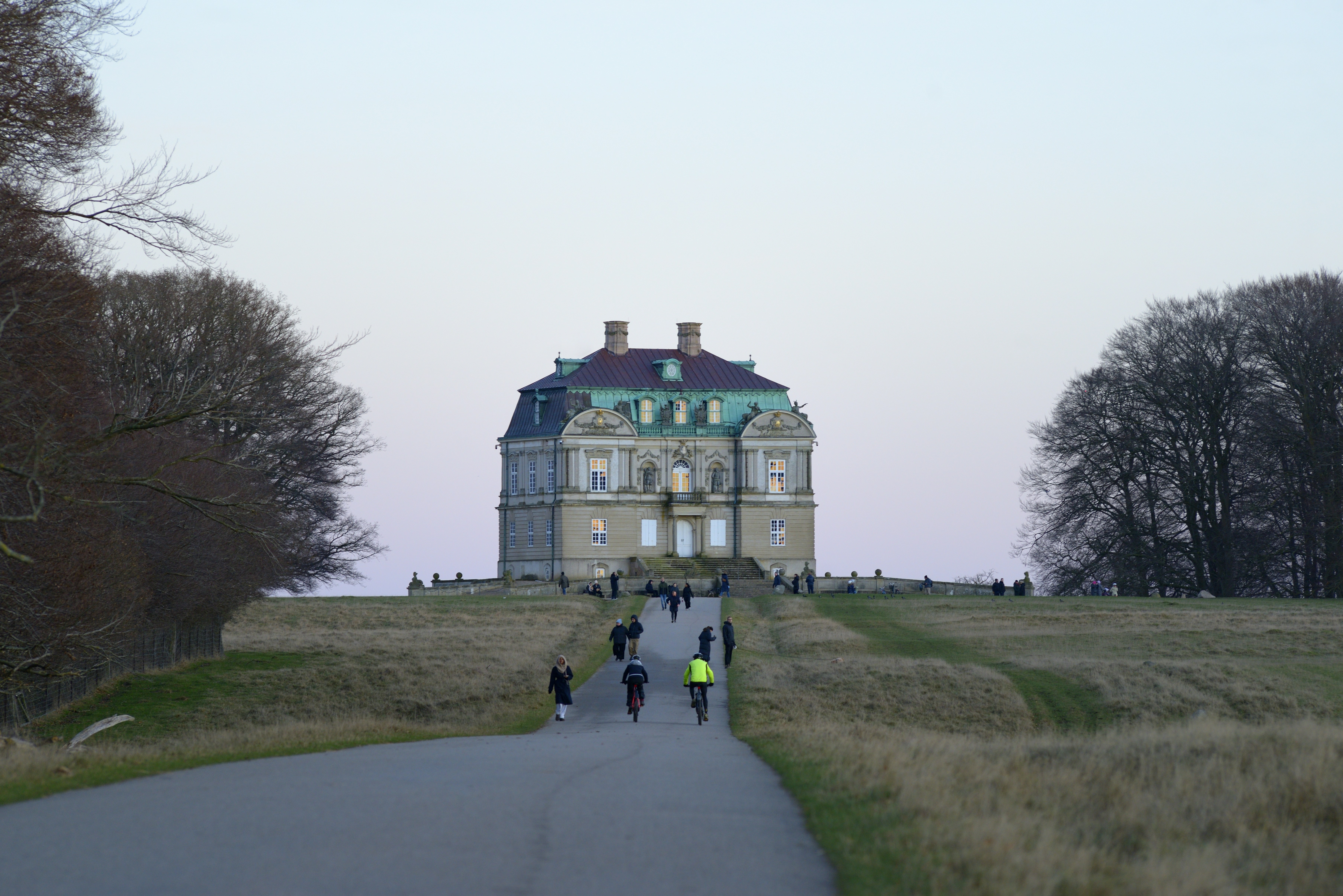 Castle at the Hill: A Line of Pedestrians Climb Toward a Green-Roofed Estate