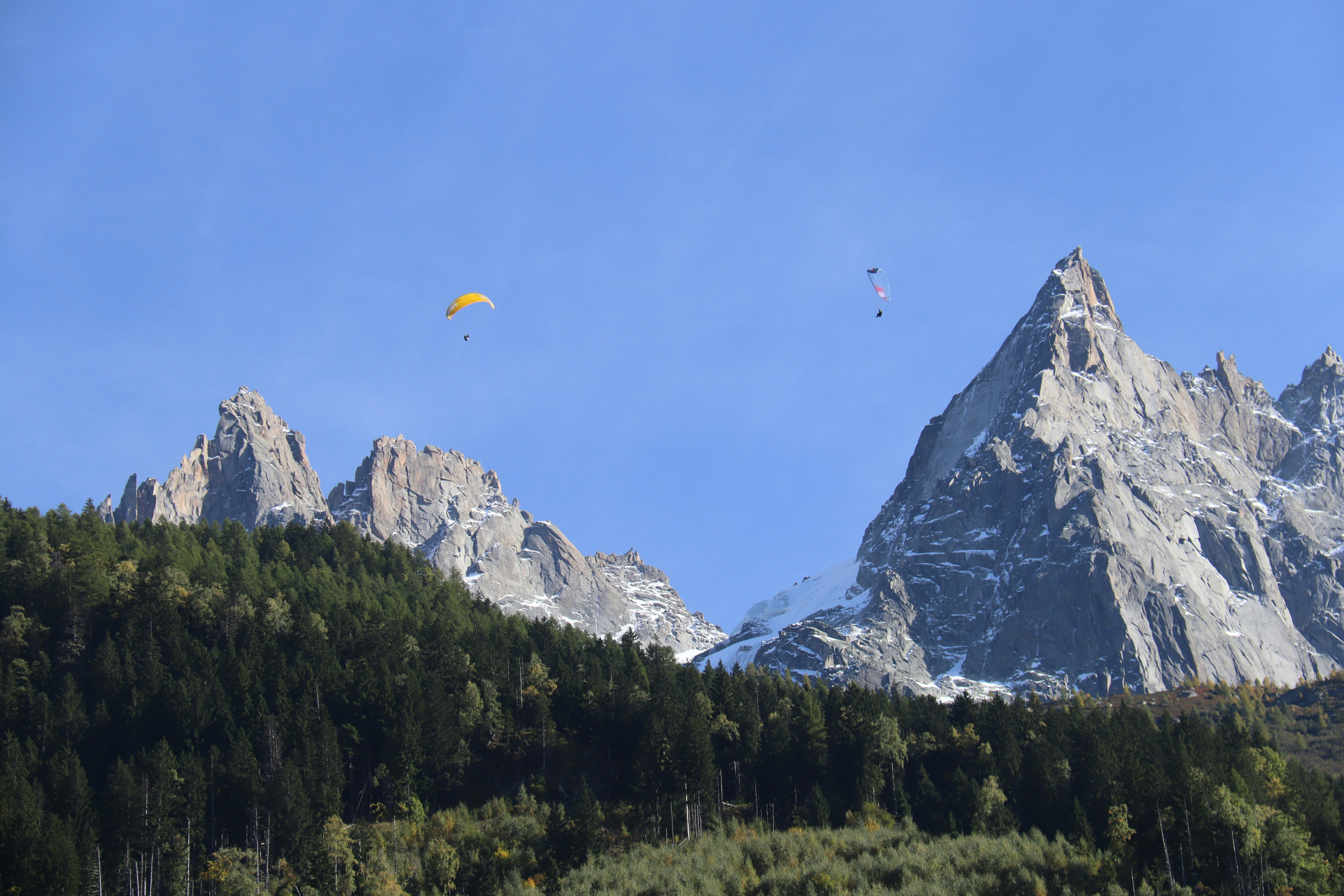 Yellow paraglider against jagged alpine peaks