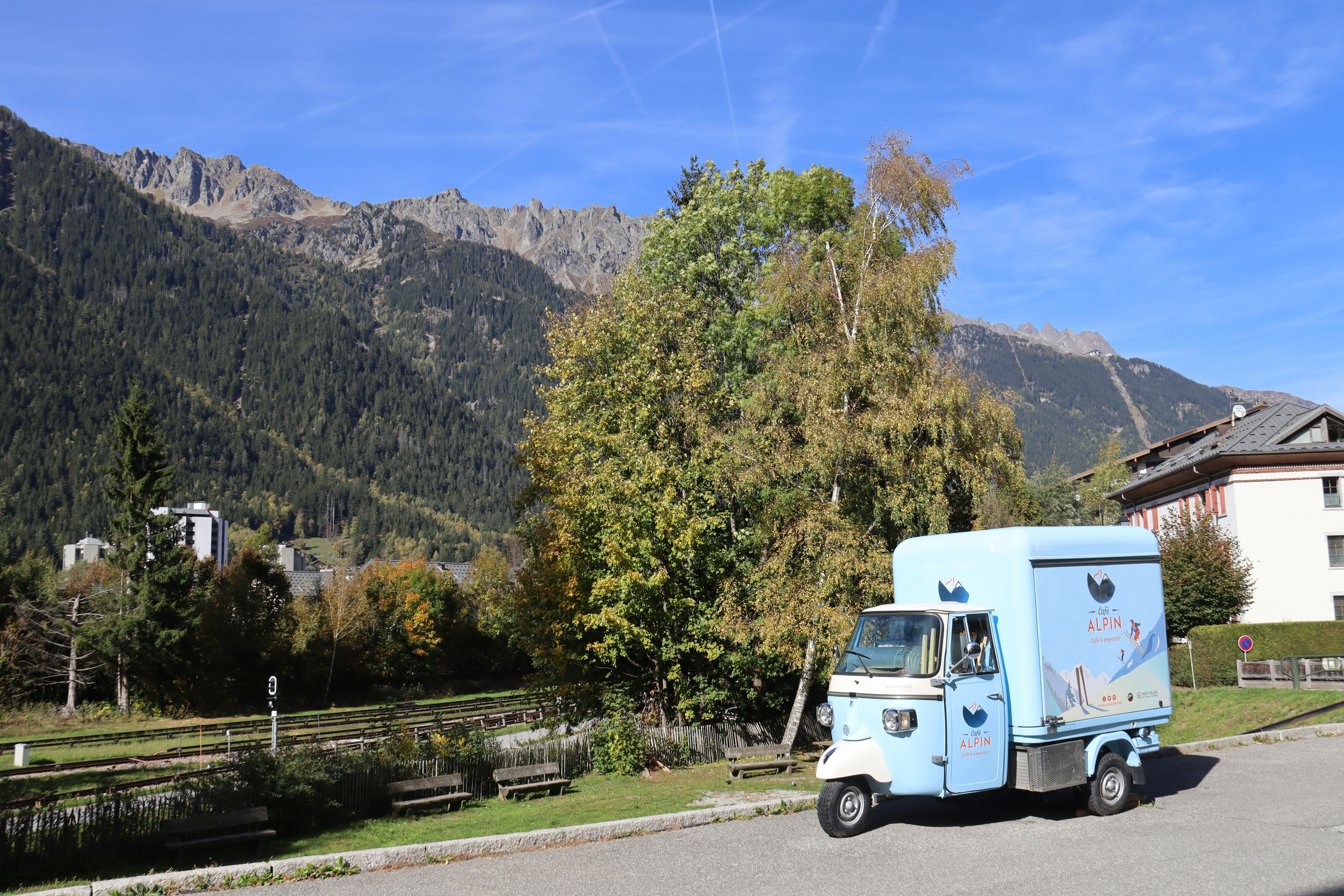 A light blue three-wheeled vehicle parked on a street.Shalev Cohen