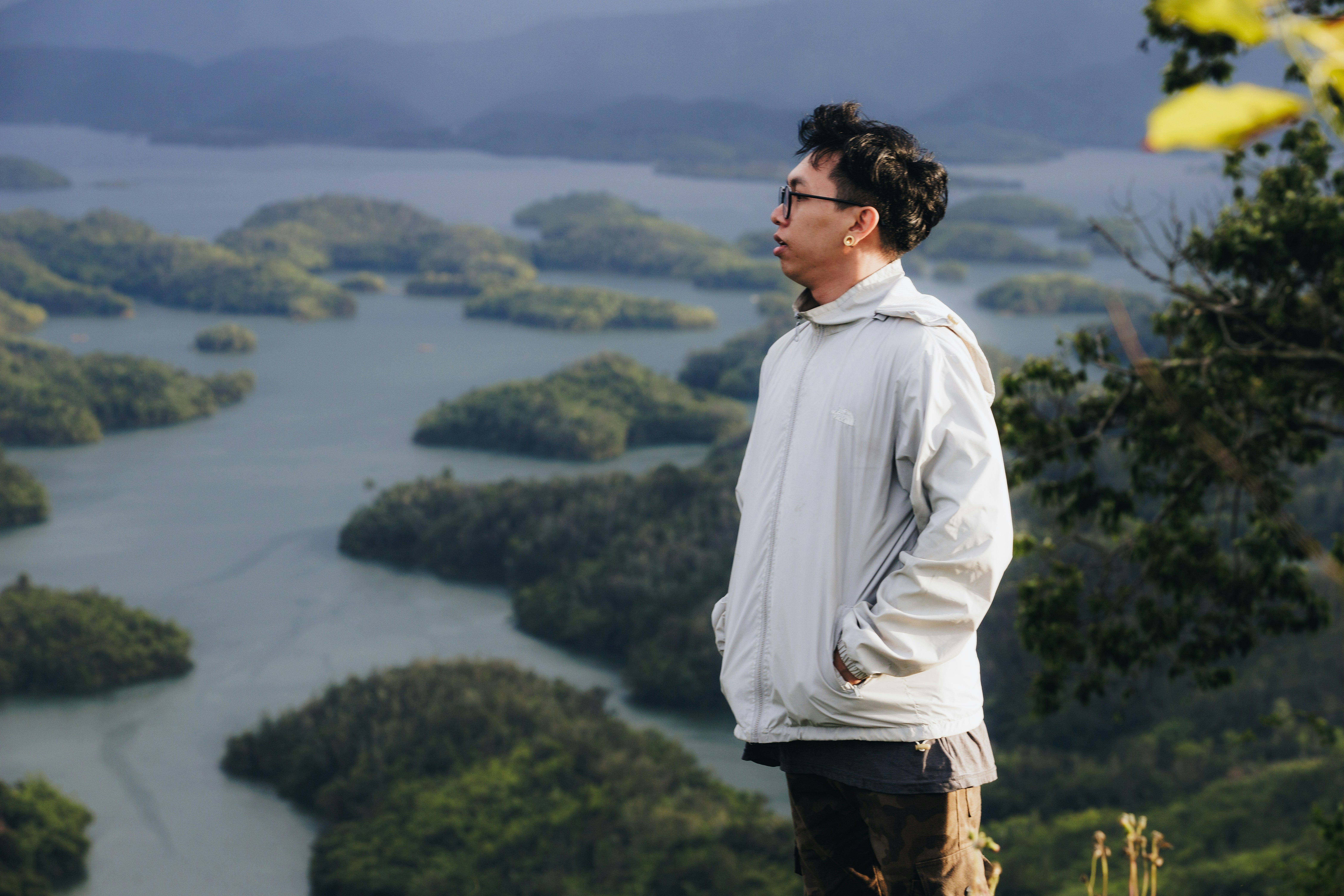 Glimmering overlook: a lone hiker surveys emerald archipelagos from a cliff