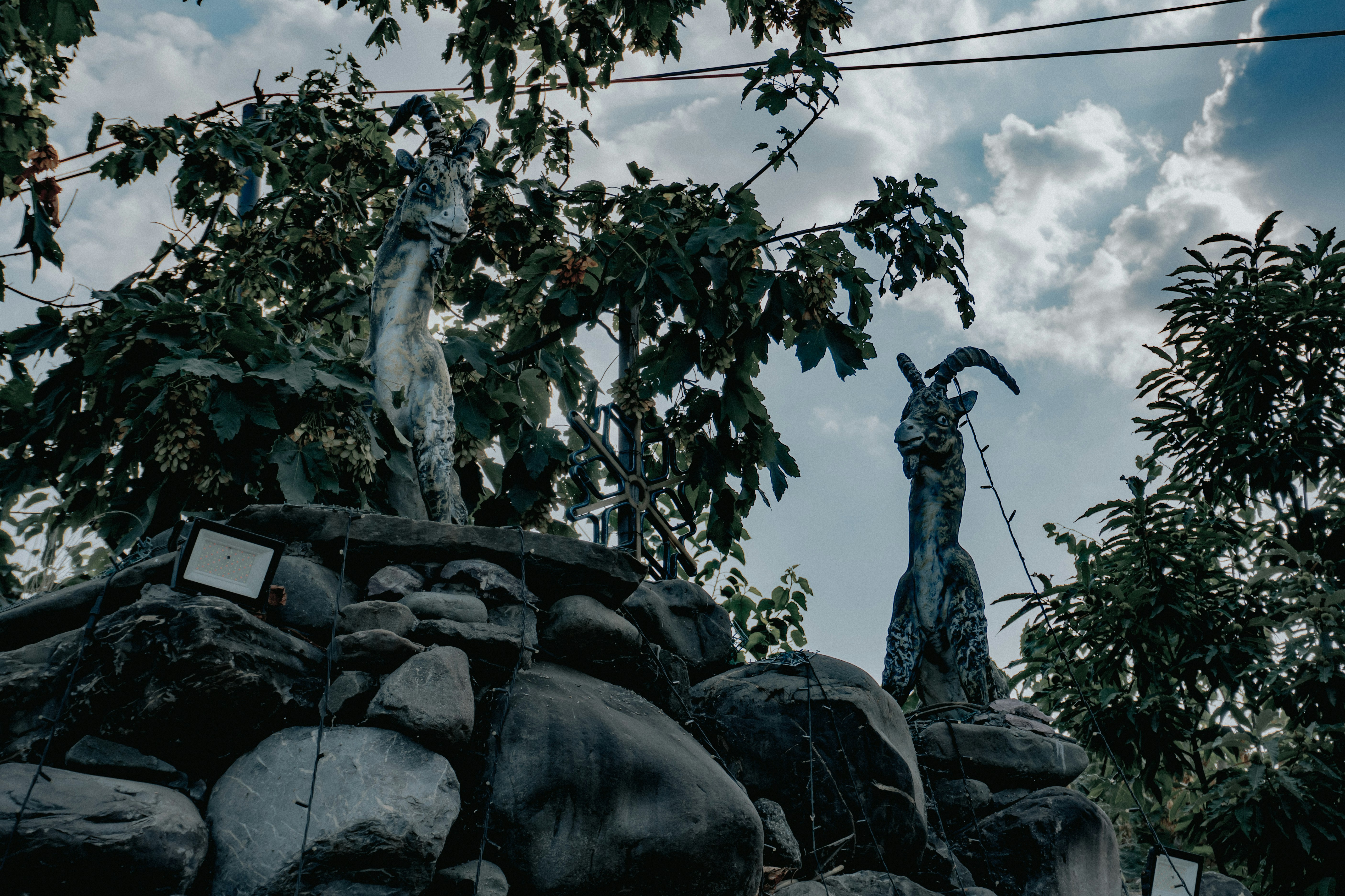 Statues atop a rocky pedestal under a cloudy sky