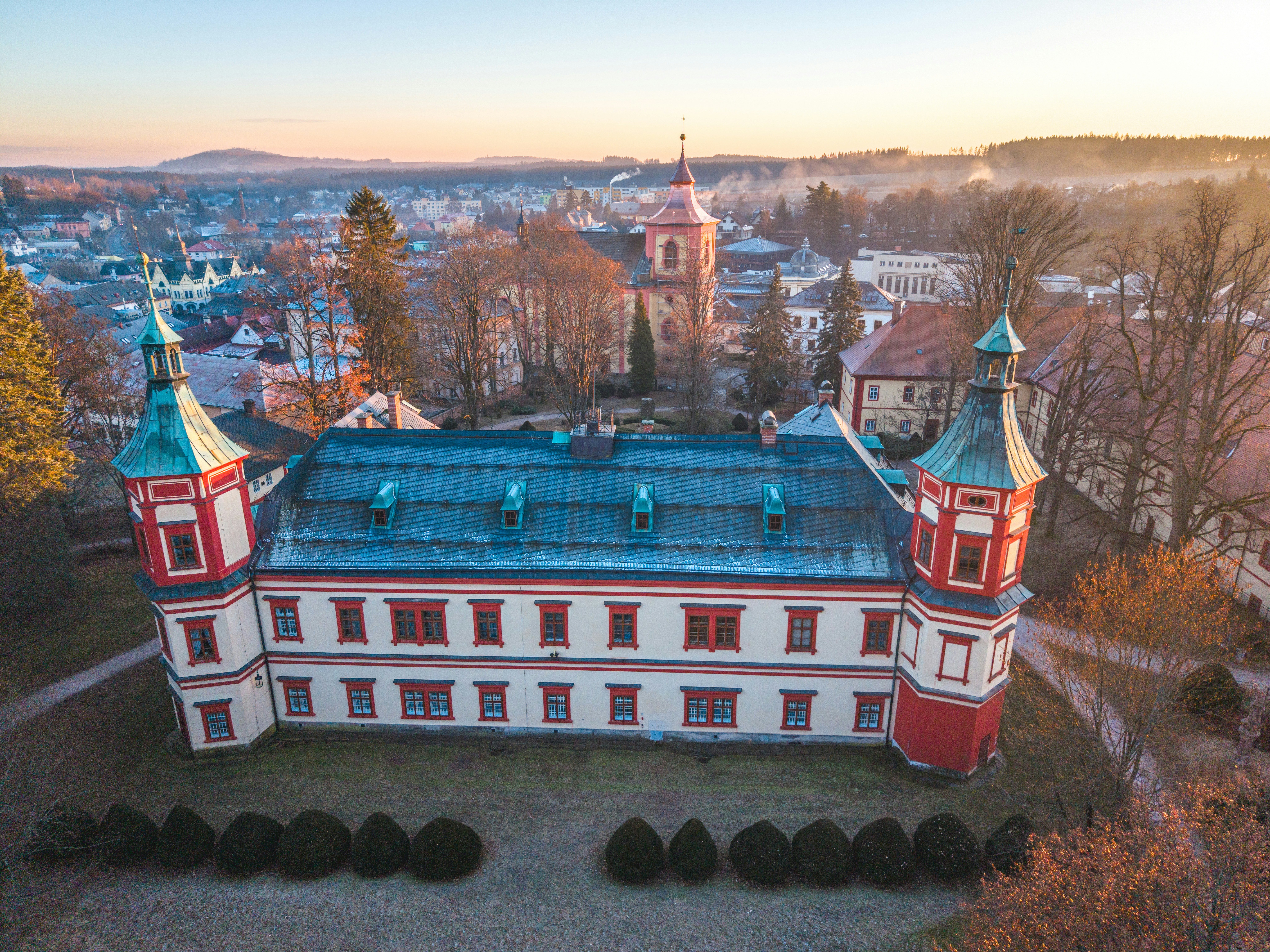 Aerial view of Jilemnice Castle during golden hour in early winter with warm afternoon light.