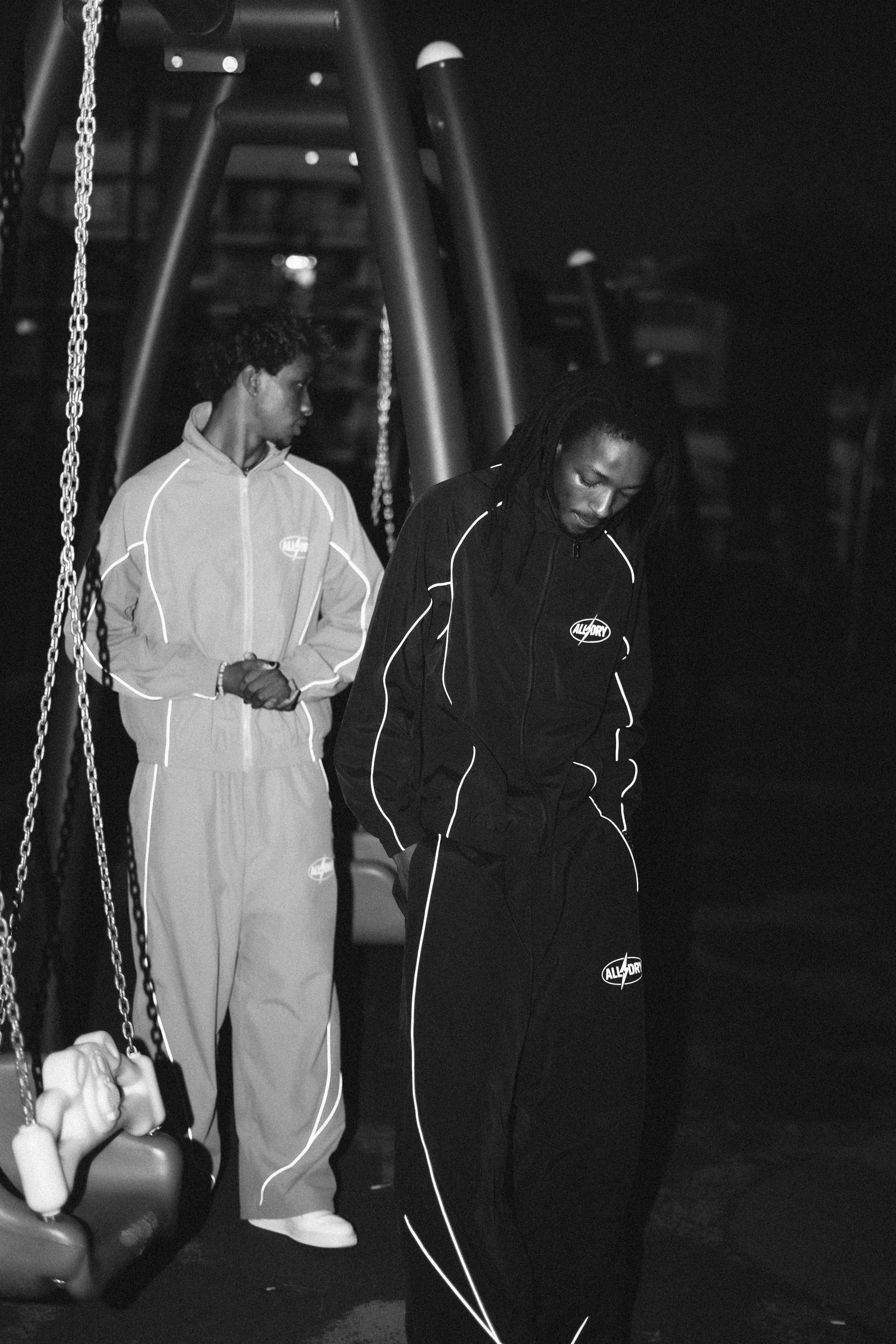 Two joggers pause by a playground lantern as night settles