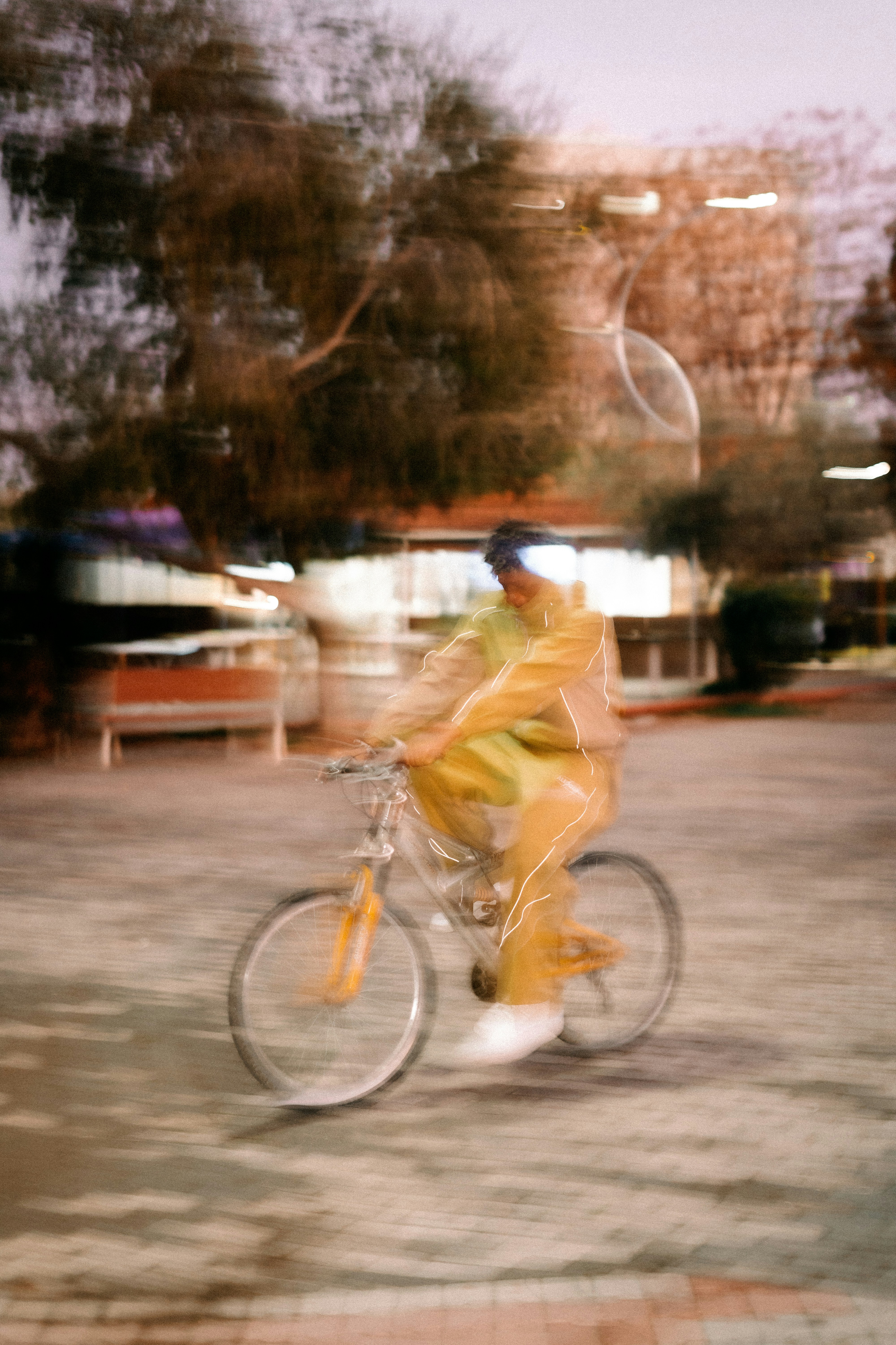 Blurred Ride: A Yellow-Cloaked Cyclist in a Motion-Blur Nightscape