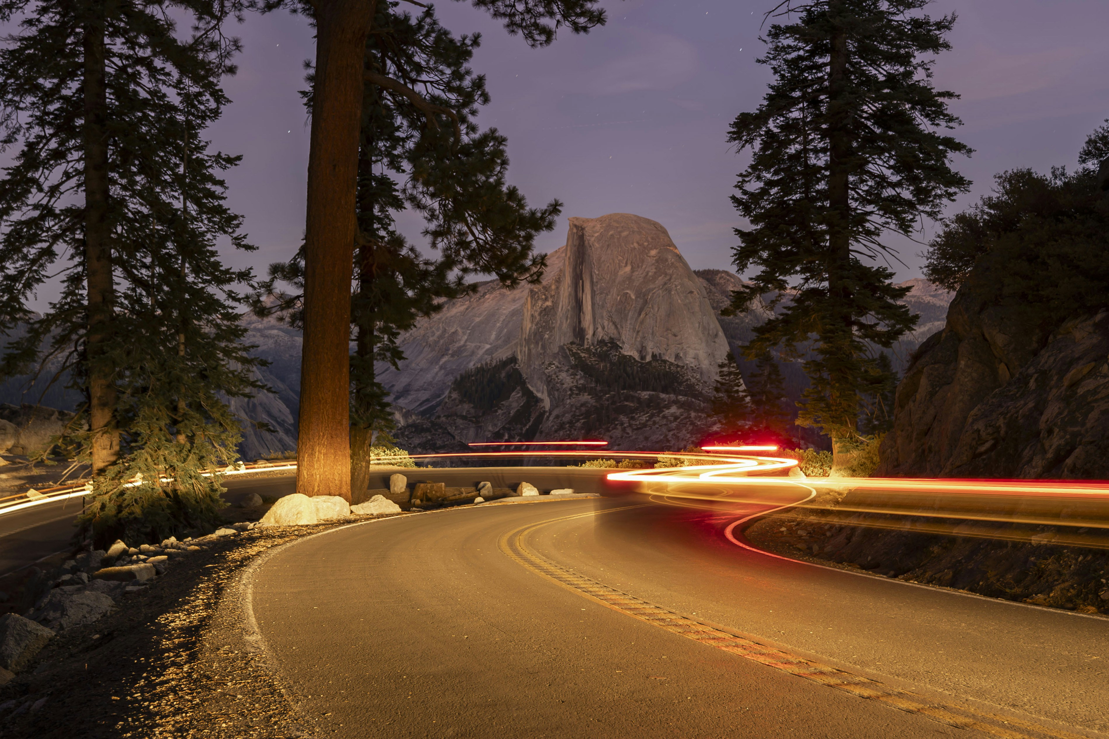 Curved Mountain Road: Light Trails Beneath a Sunset Peak