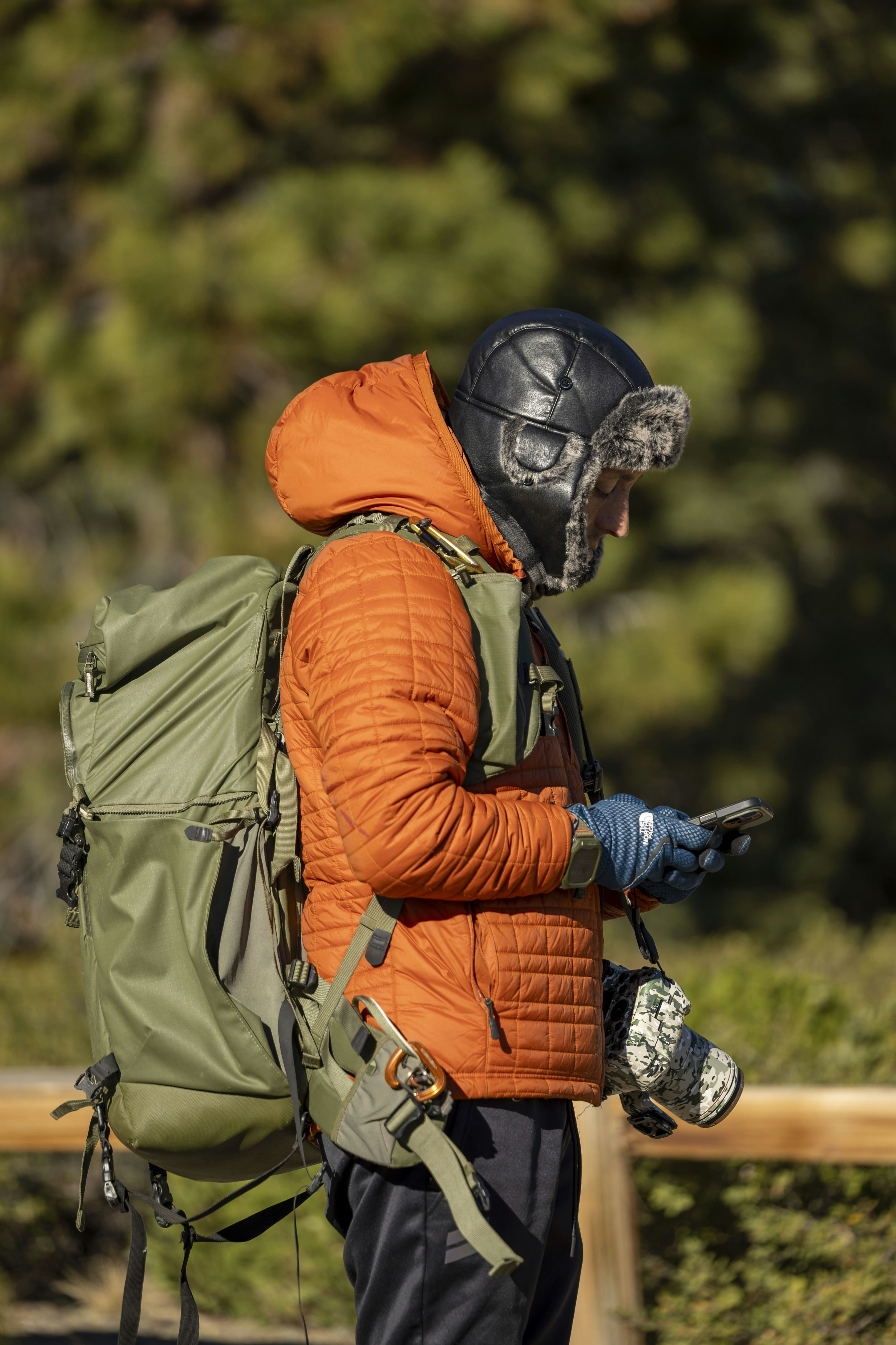 Person in winter gear with backpack and camera checks phone. photo ...