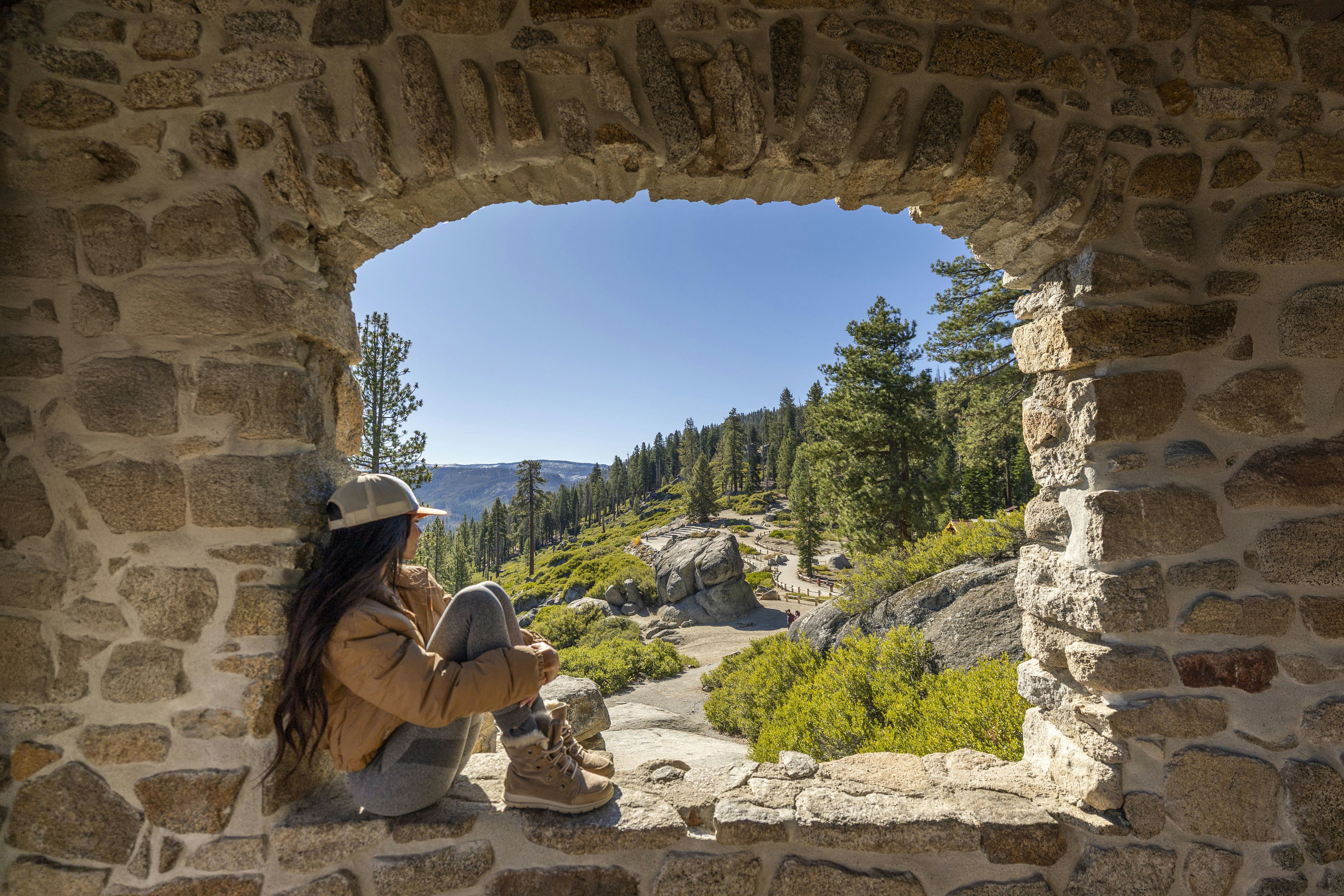 Woman looking out from stone window at forest landscape