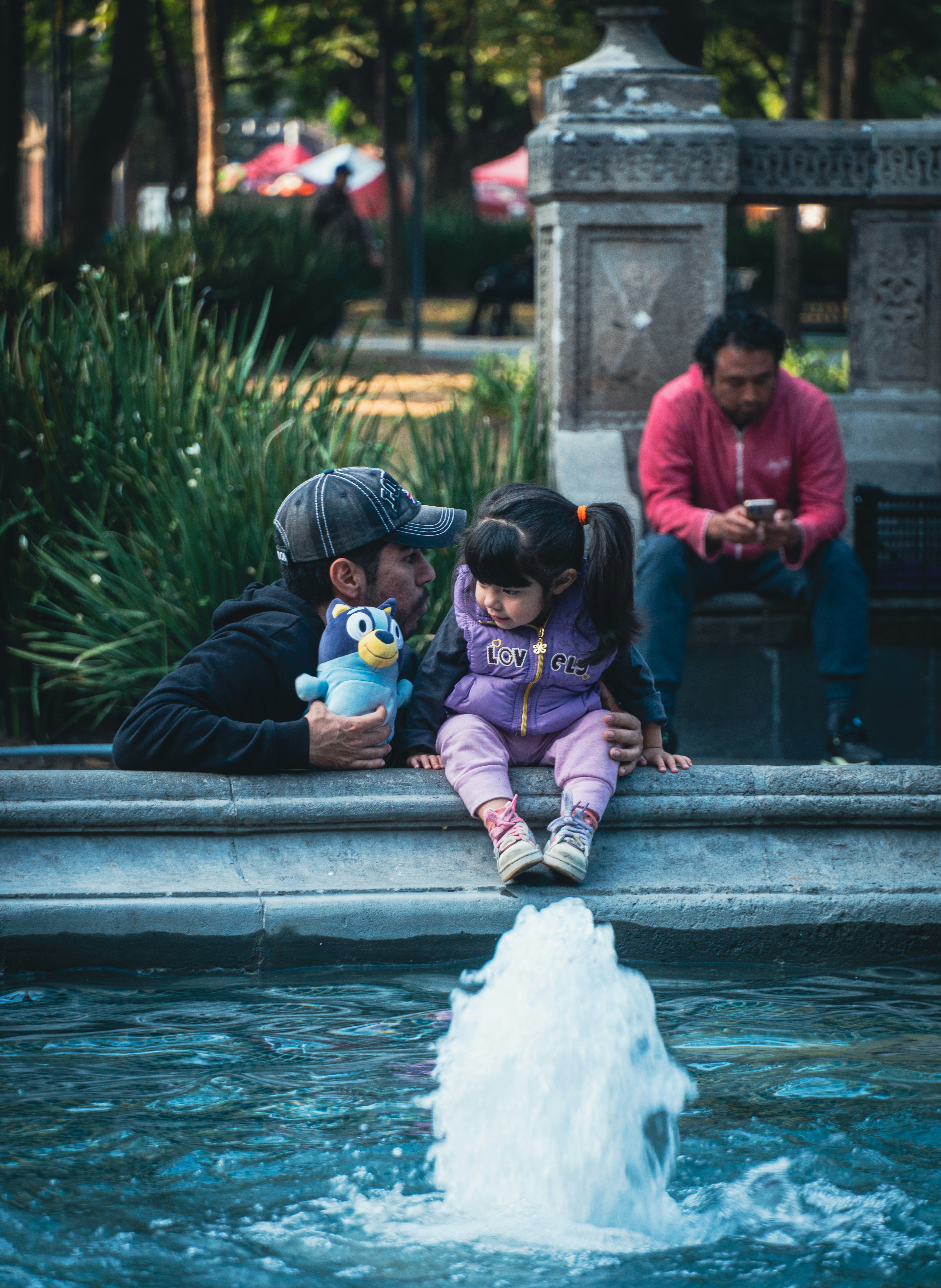 A Father and Daughter Share a Quiet Moment by the Fountain