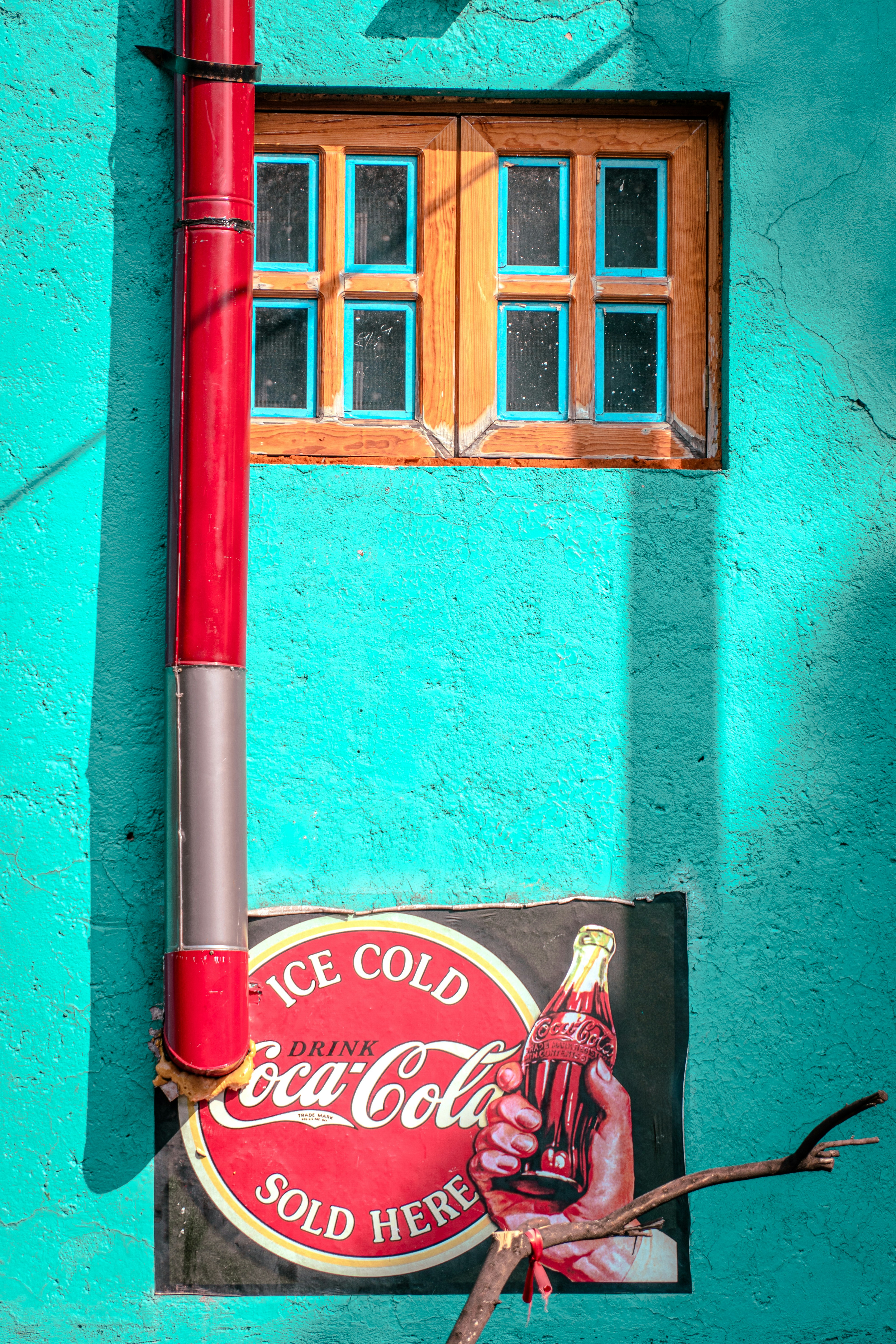 A Turquoise Wall, Red Pipe, and Retro Coca-Cola Sign