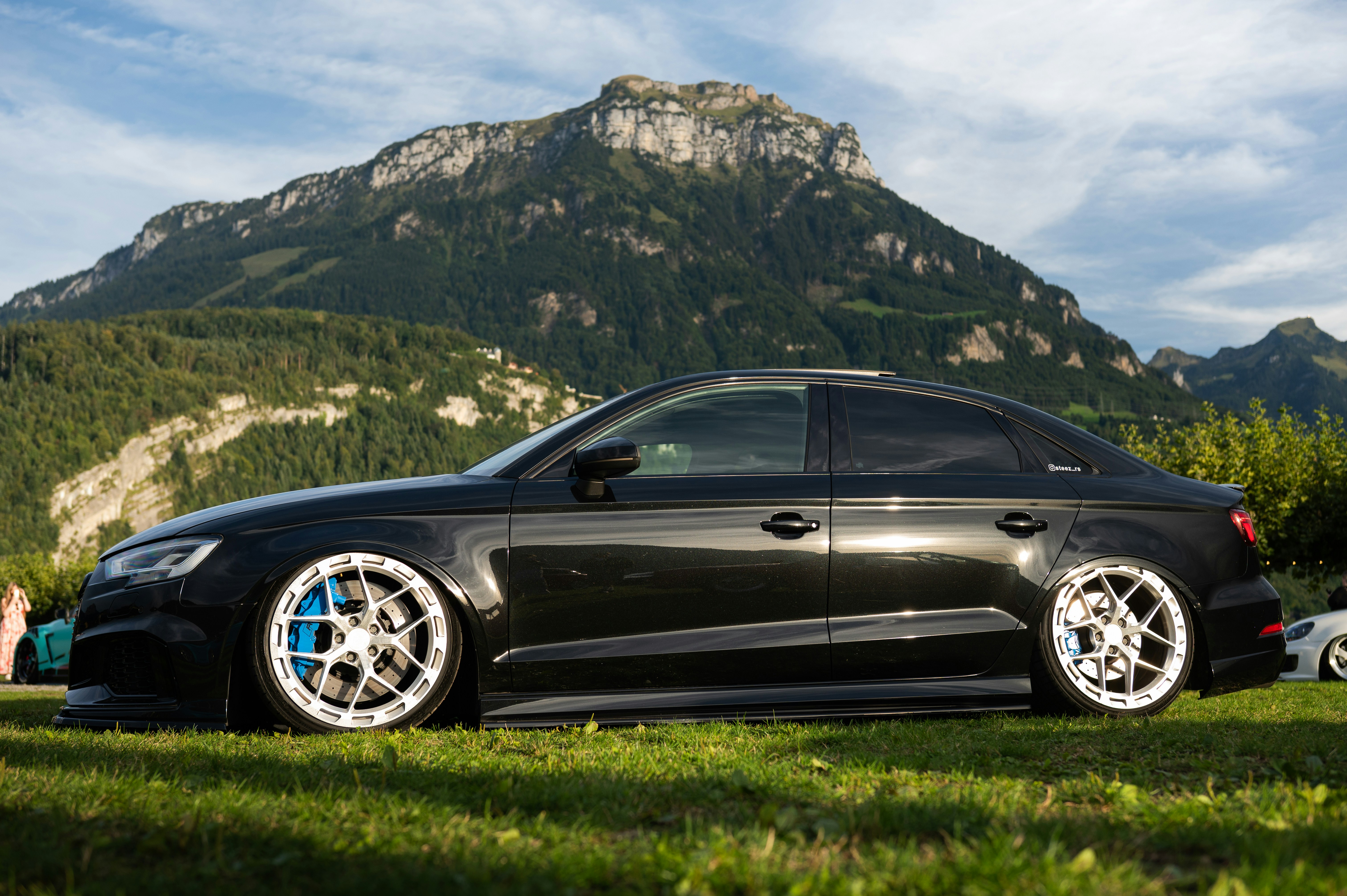 Low-slung black coupe under alpine sky