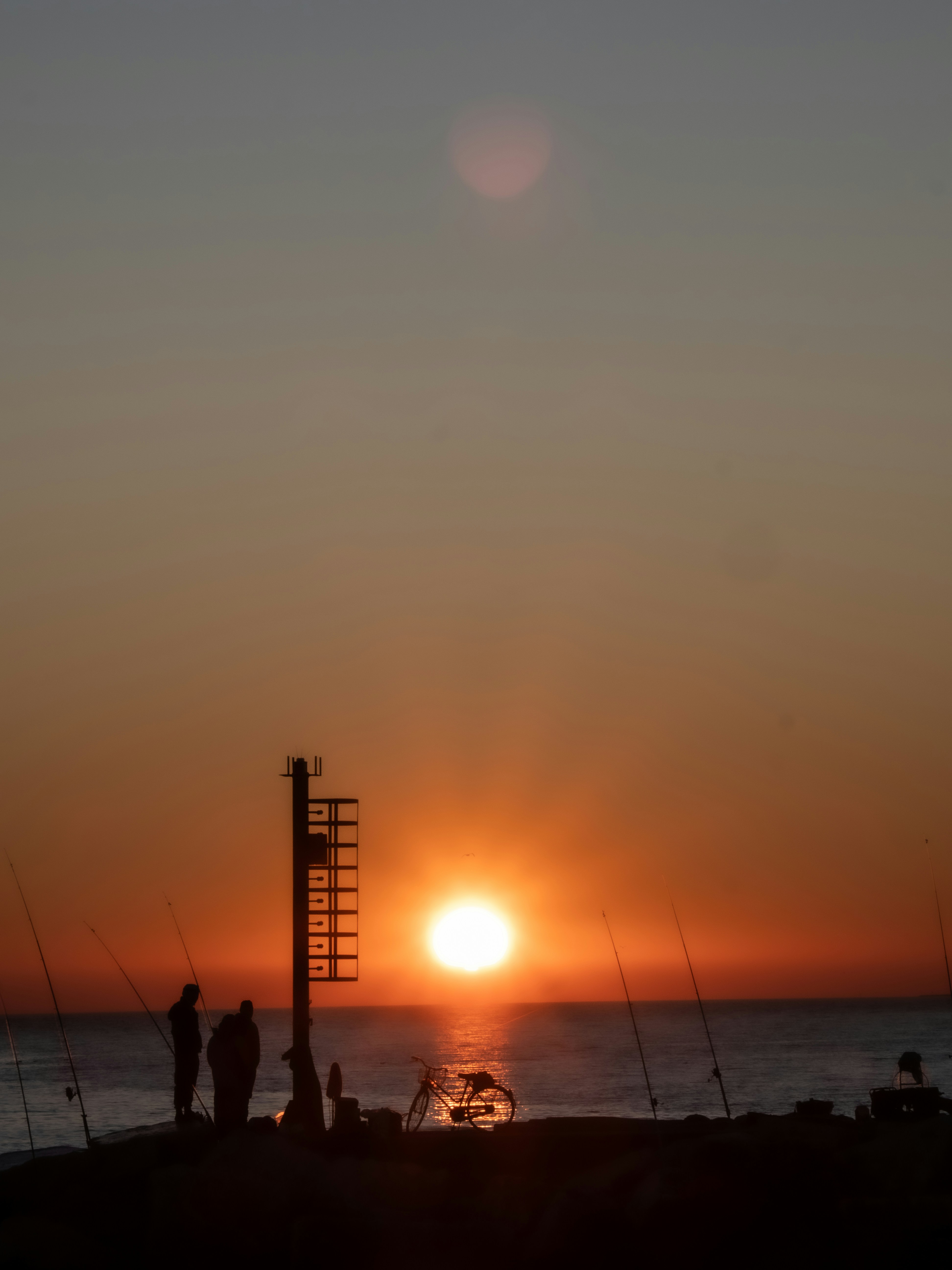 Sunlit silhouettes on the pier at blue-to-orange dusk