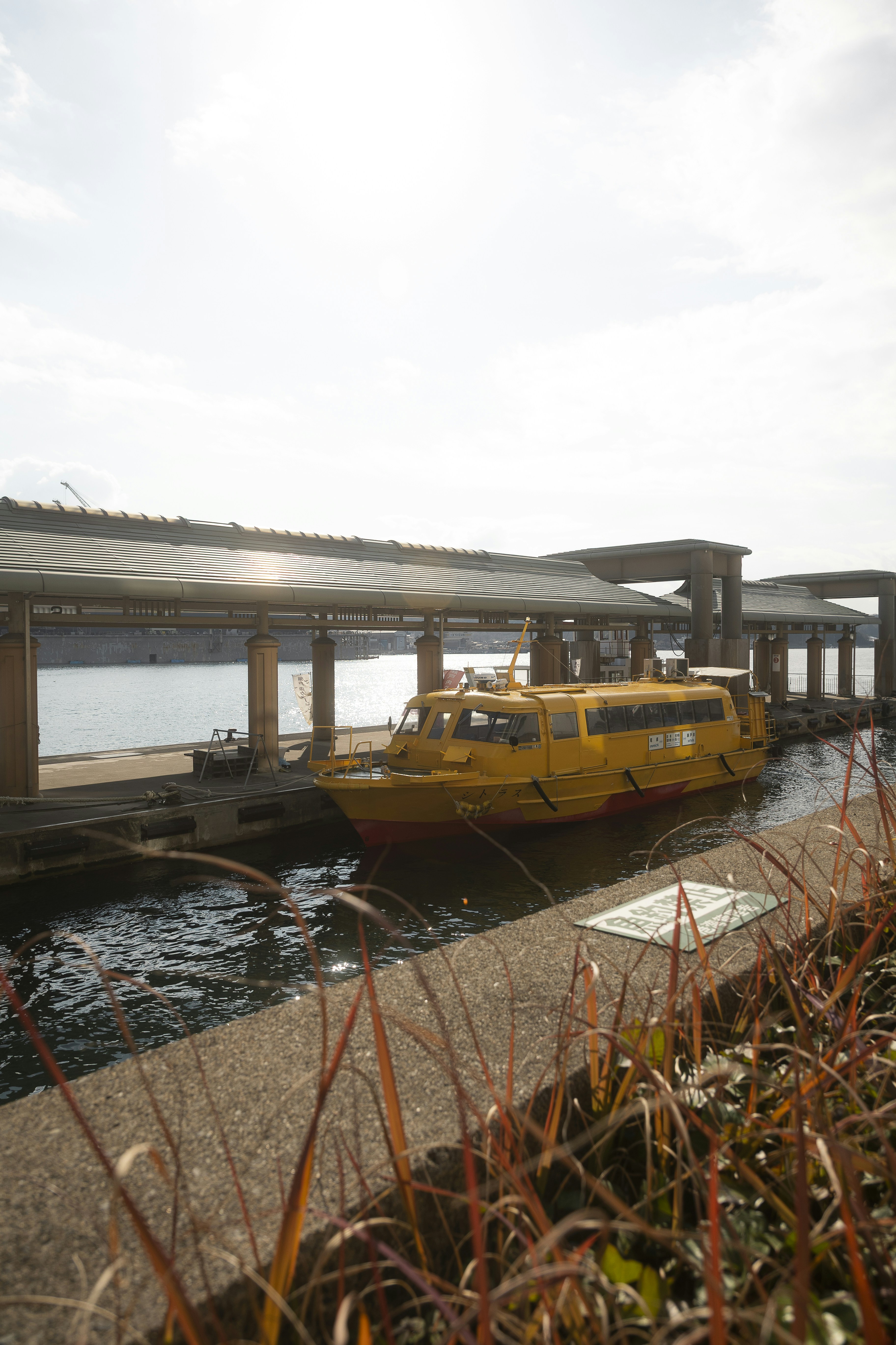 Yellow boat docked under a sunlit pier