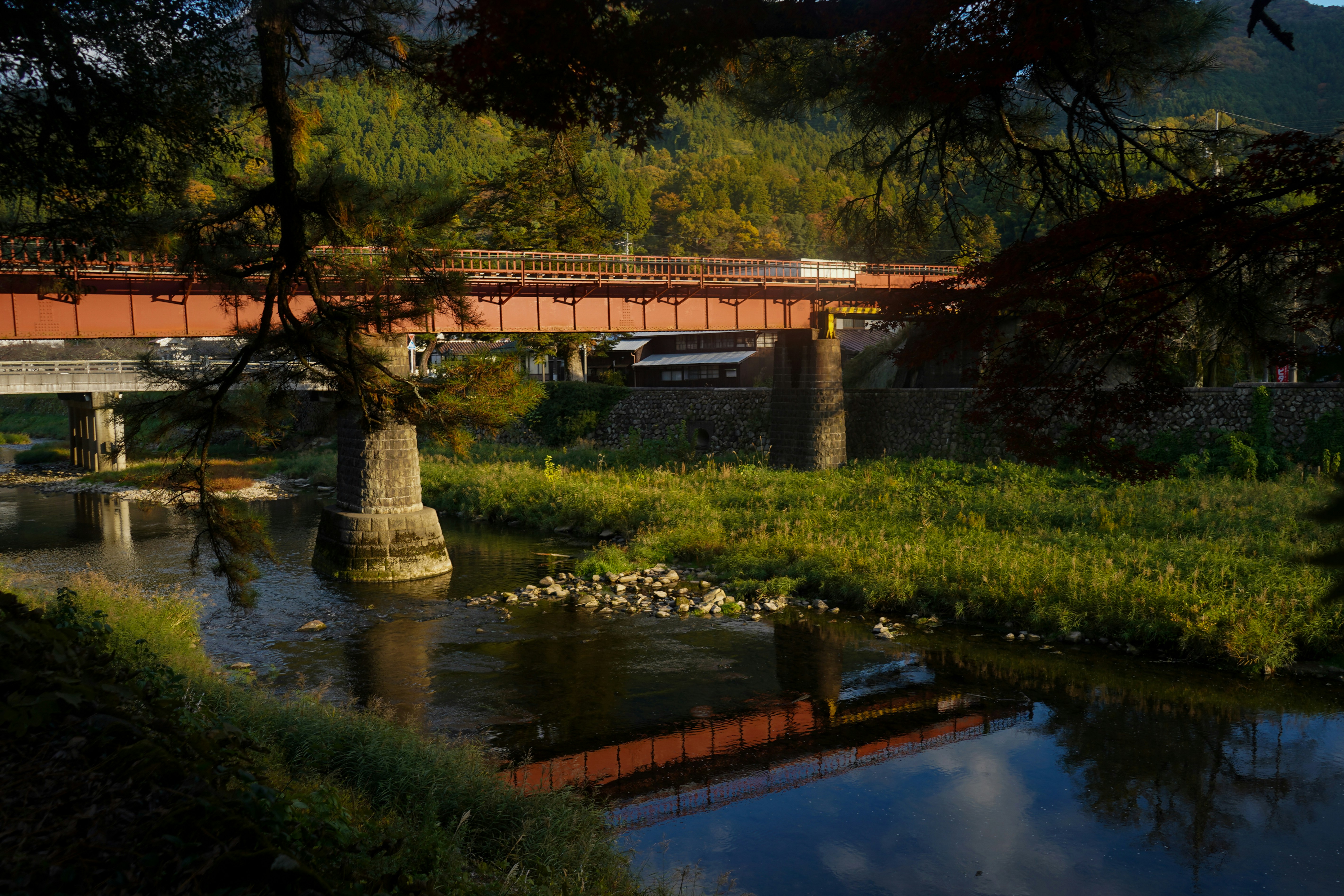 Reflections Under the Red Span: A Tranquil River Bridge