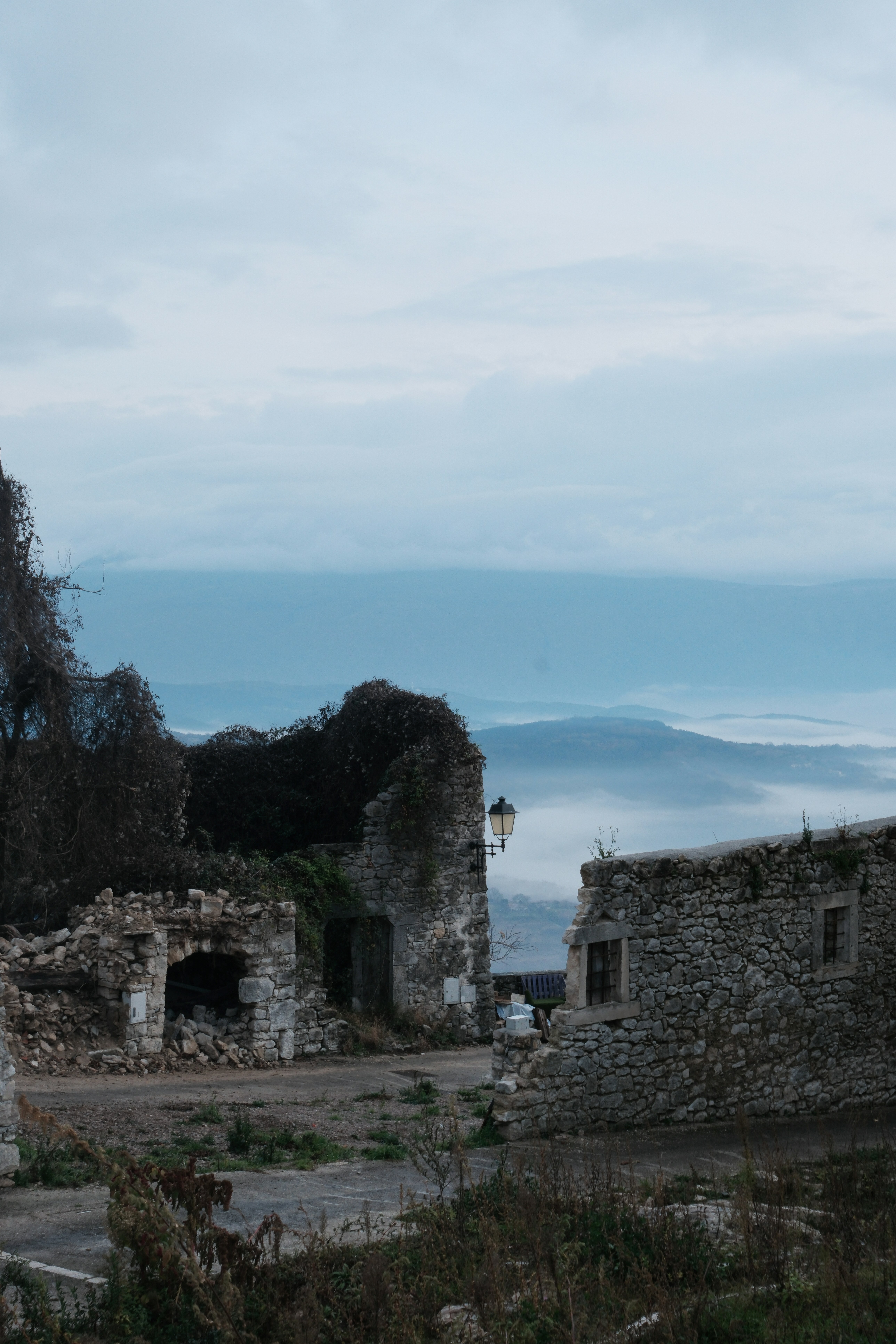Ruined village at dawn: stone walls and distant mist over a quiet valley
