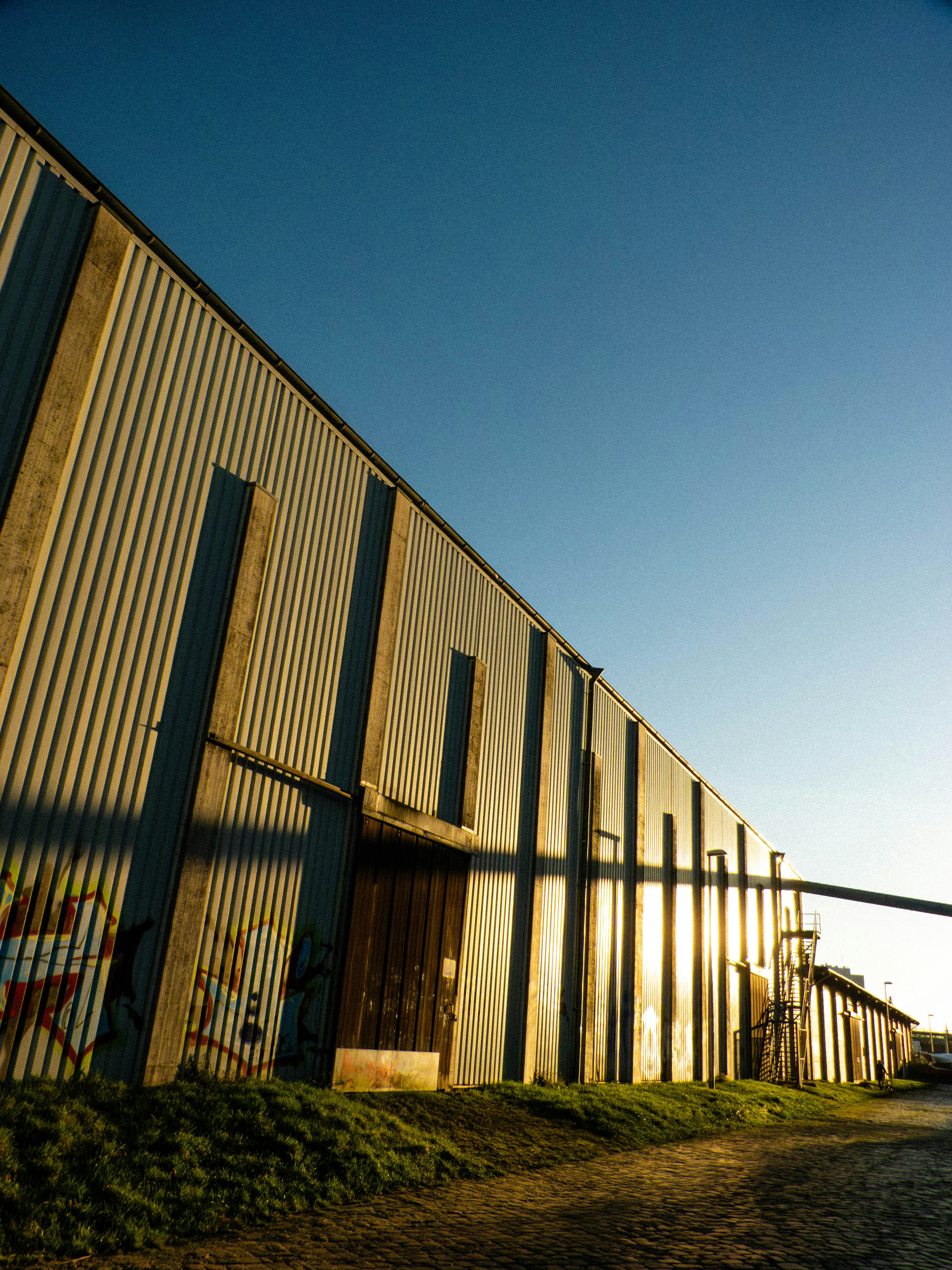 Long industrial building with graffiti under clear sky