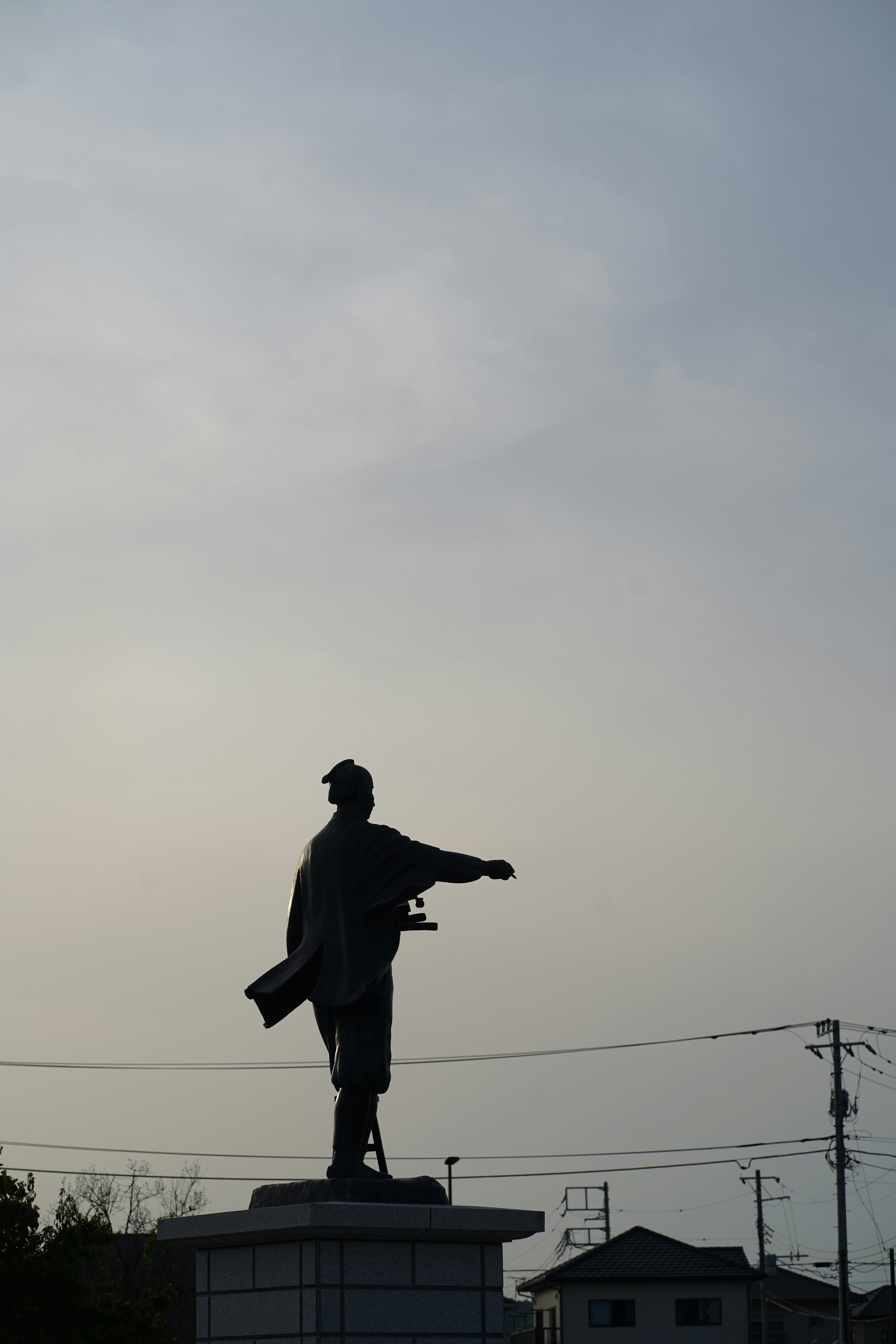 Silhouette on a Pedestal: A Figure Reaches Toward the Distant Sky