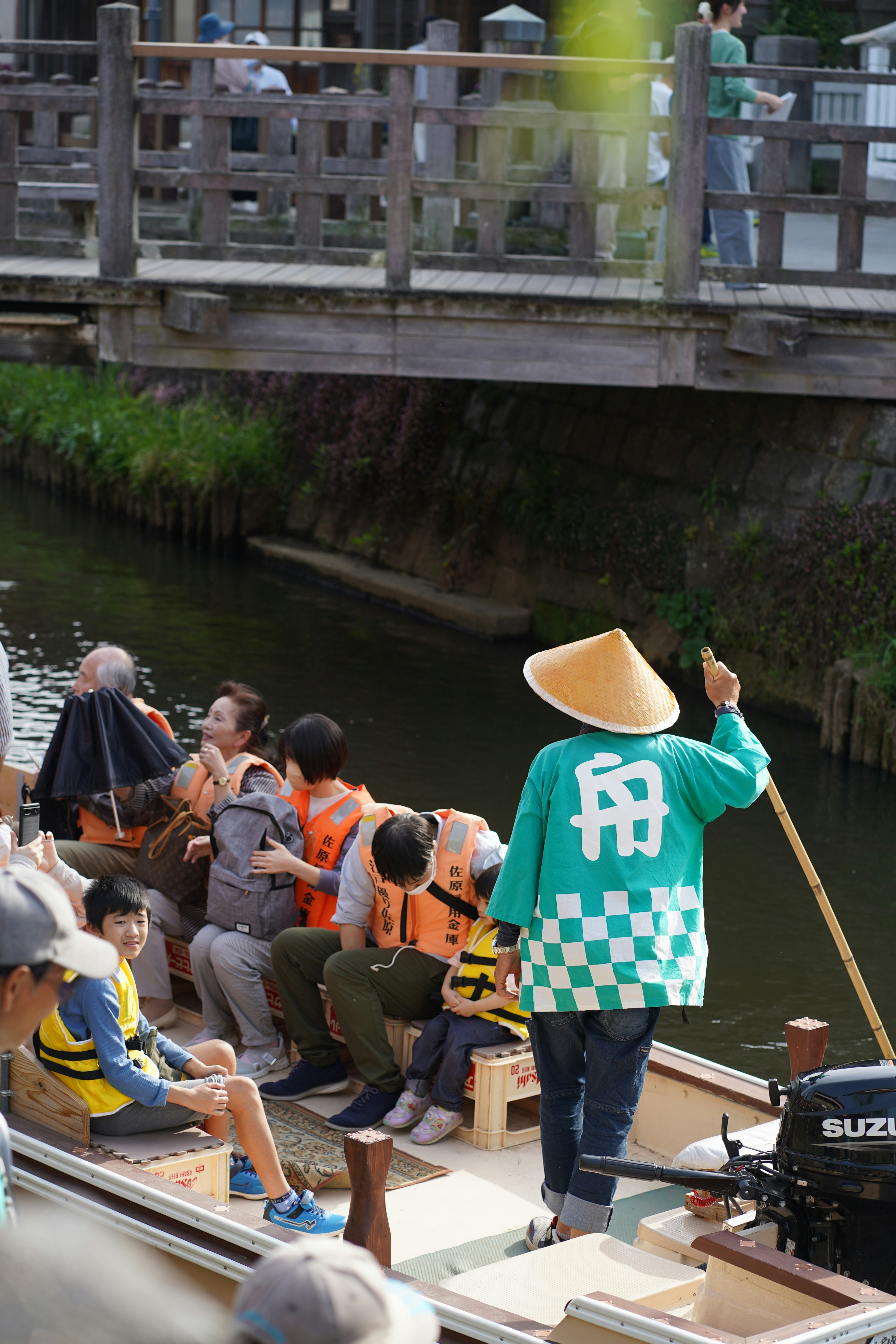 Boat Tour Guide in a Bright Teal Coat Toward the Riverbank
