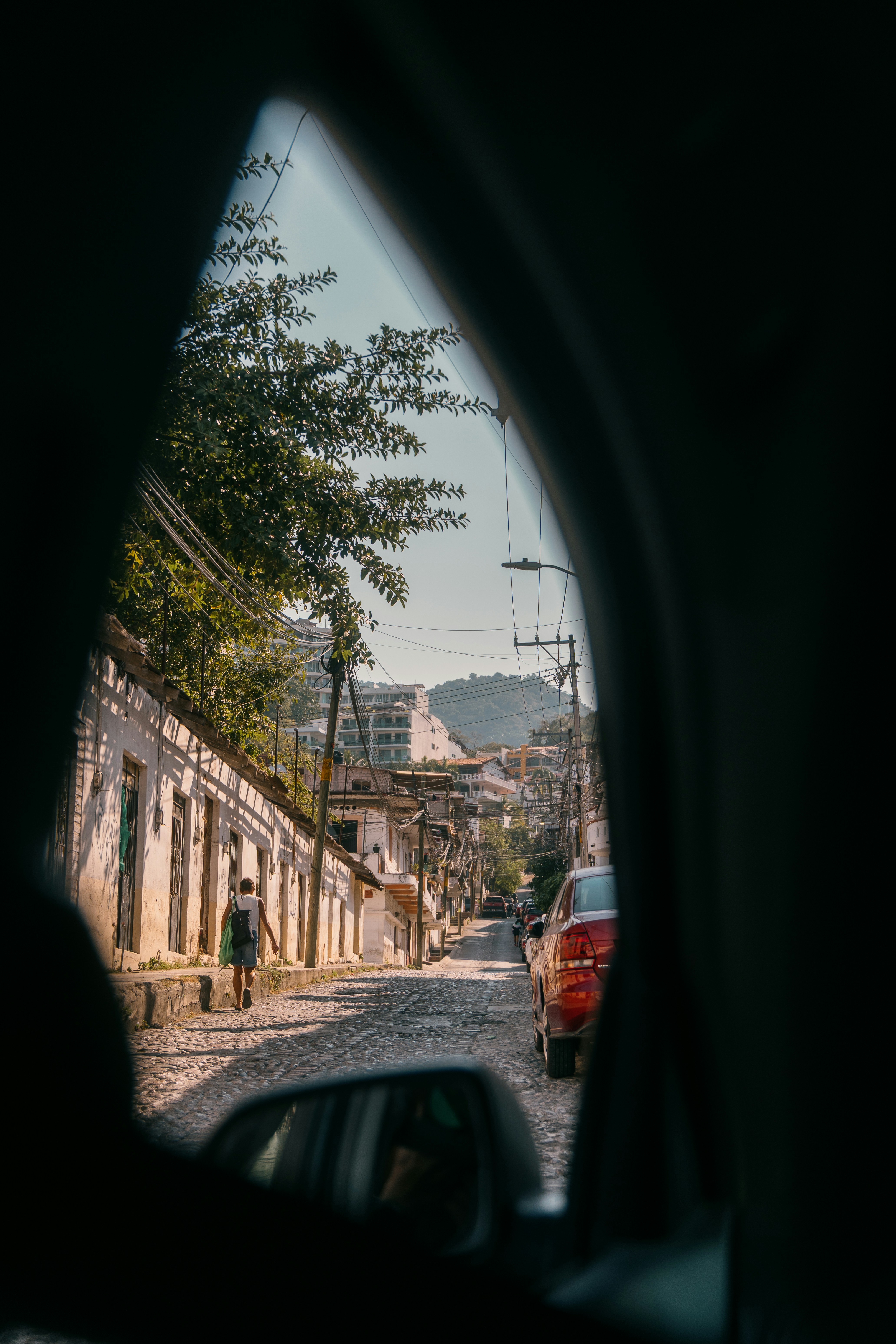 Through the Arch of dusk: a sunlit street framed by a car window