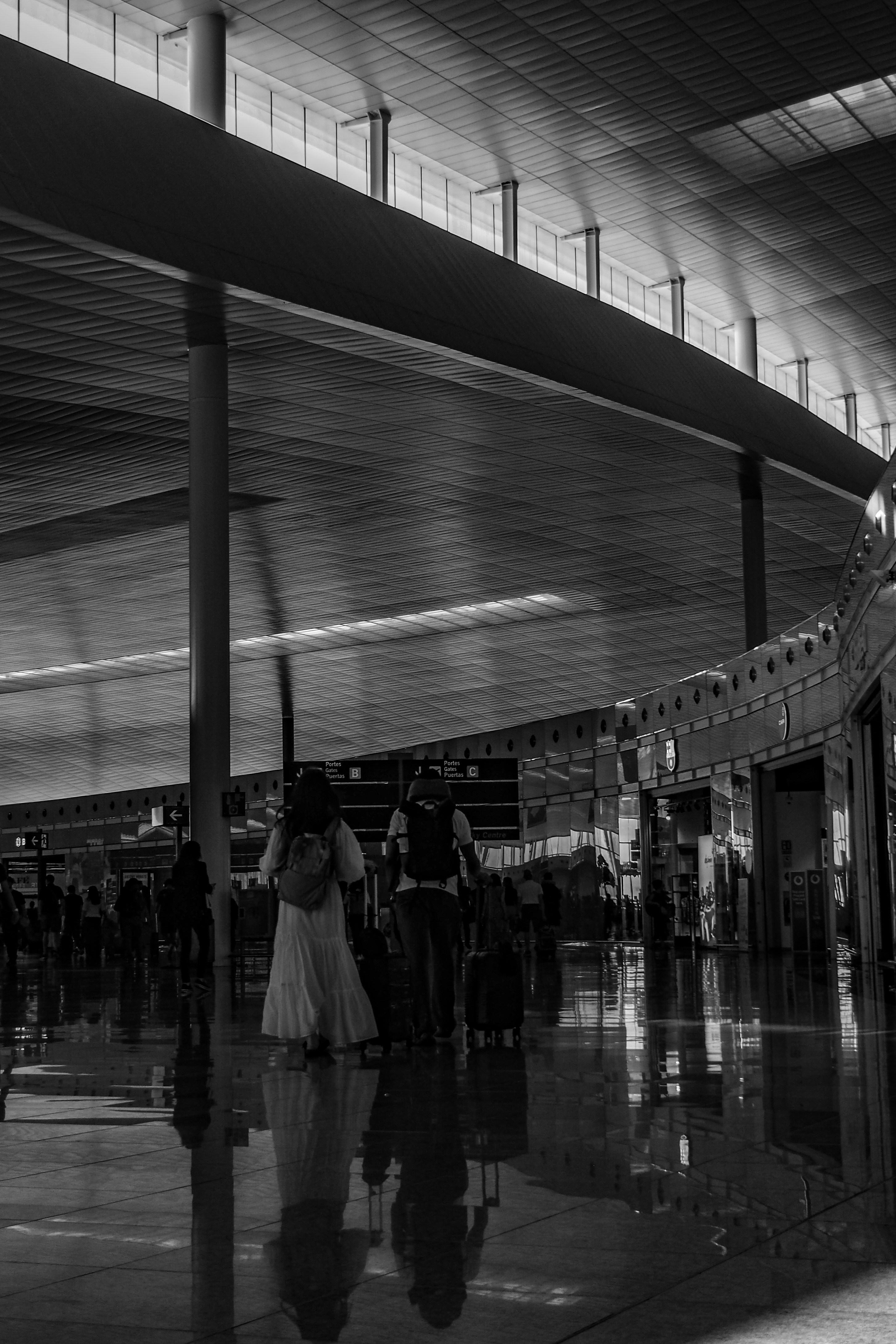 Silhouetted travelers in a polished transit hall under sweeping architecture
