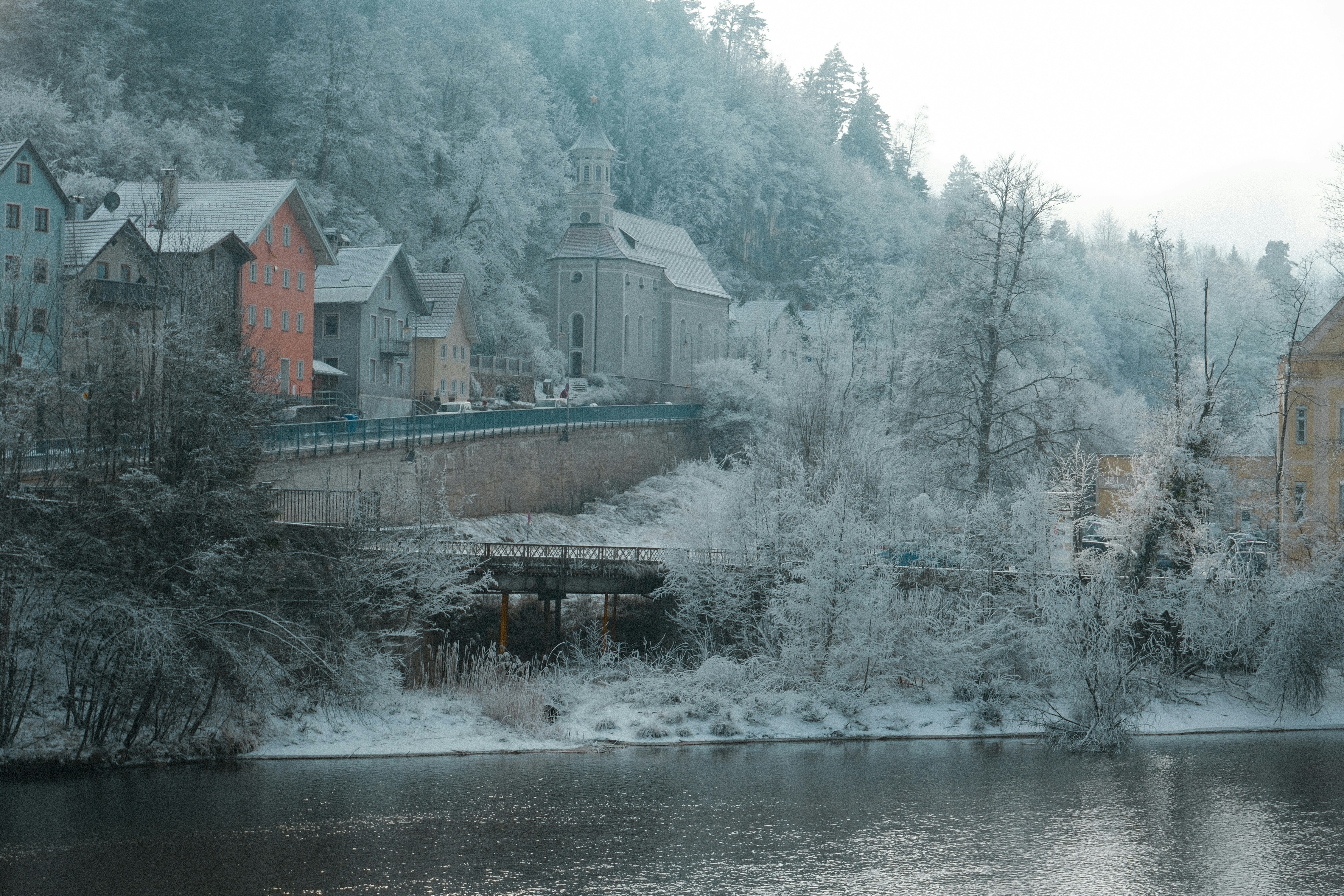 Snow-covered buildings on a hill overlooking a river.