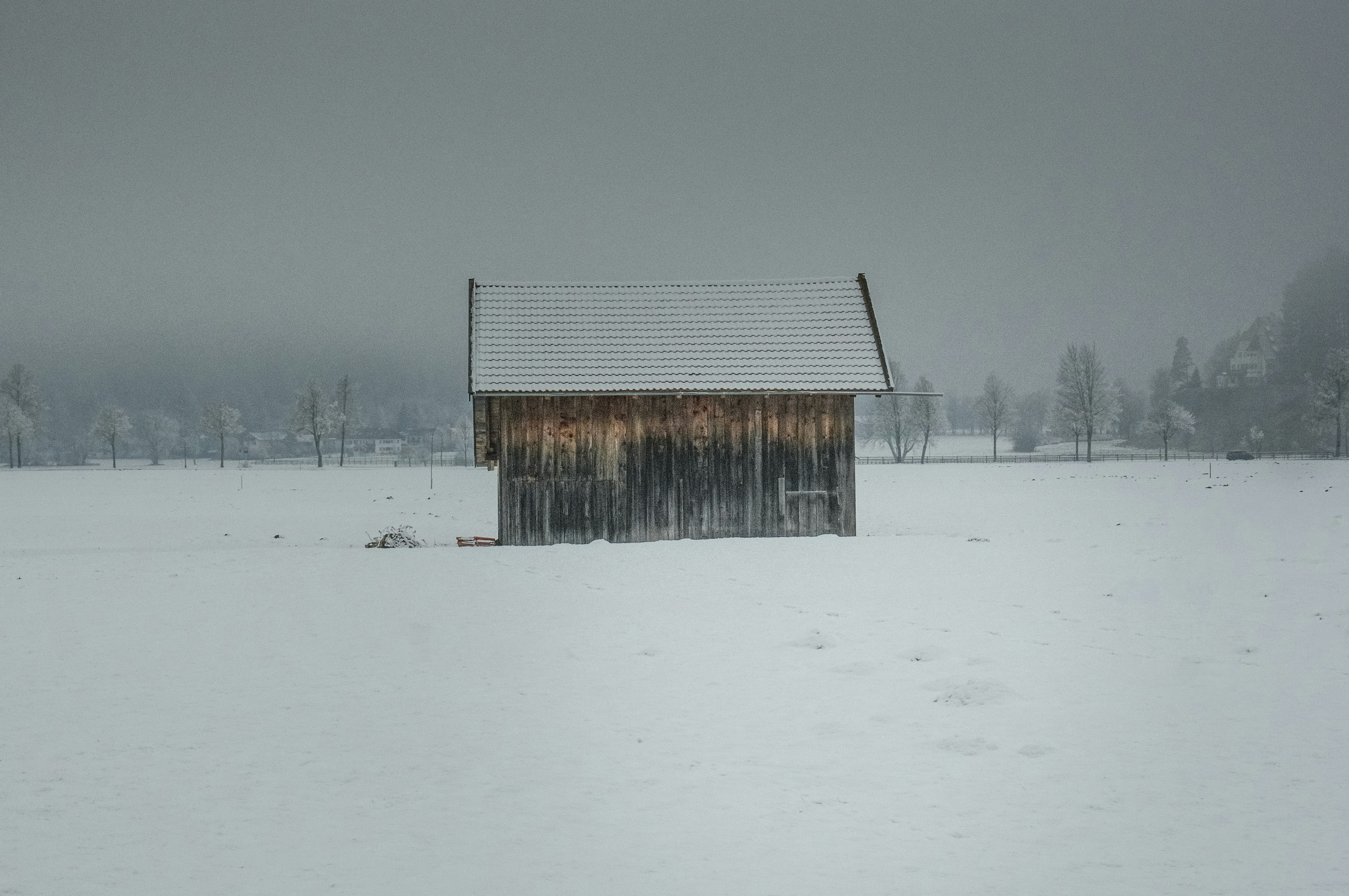 Wooden barn in a snowy field during winter
