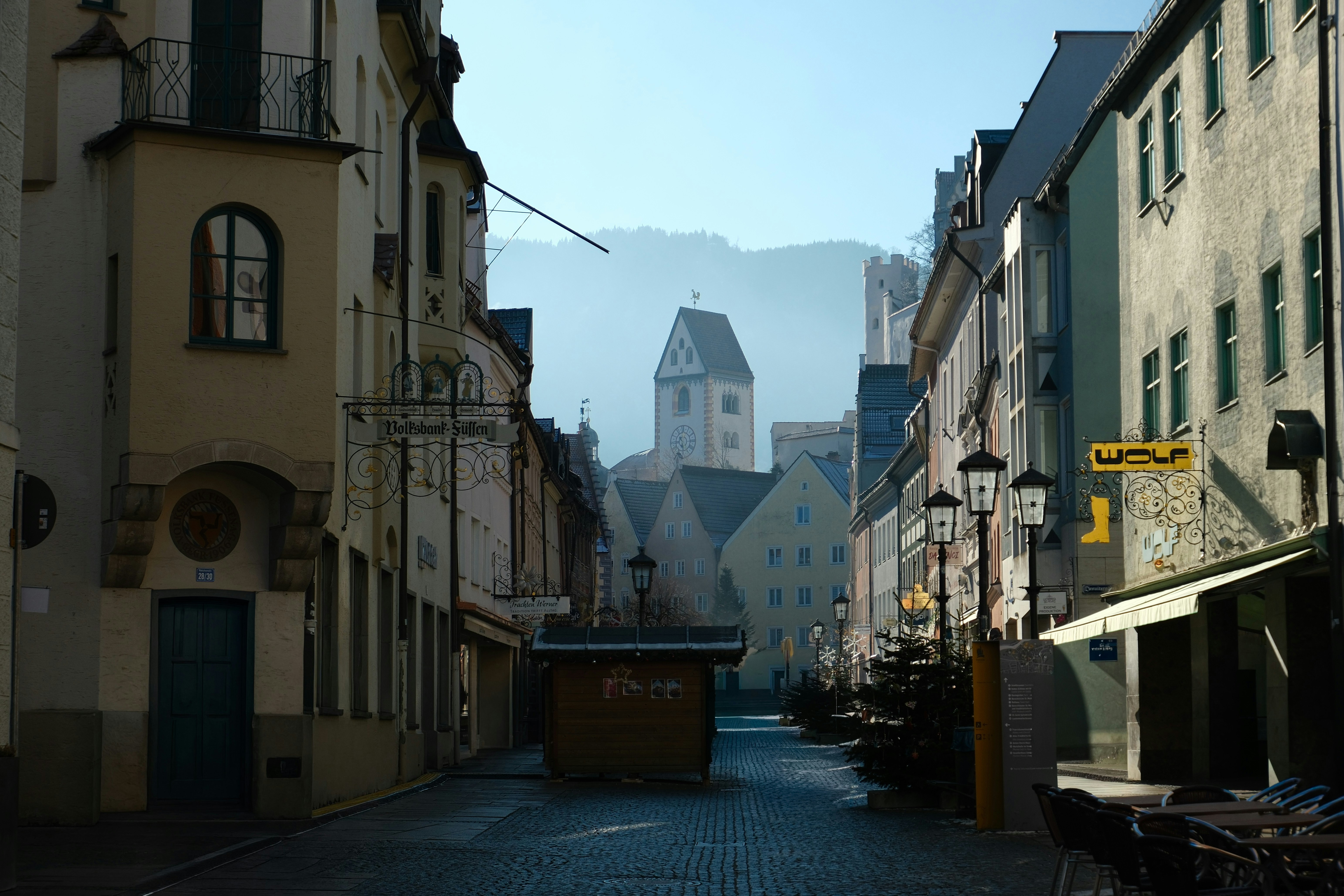 Cobblestone street leading to a church tower.