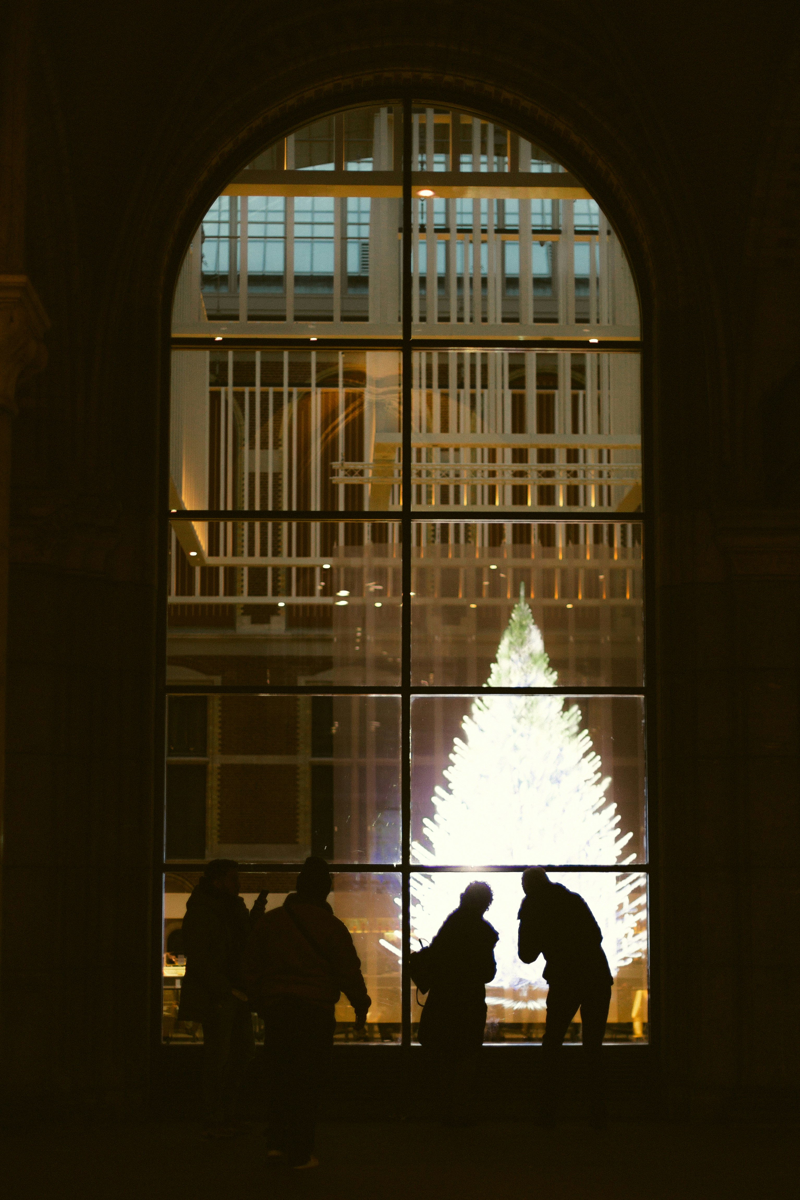 Silhouettes Beneath a Glowing Christmas Window