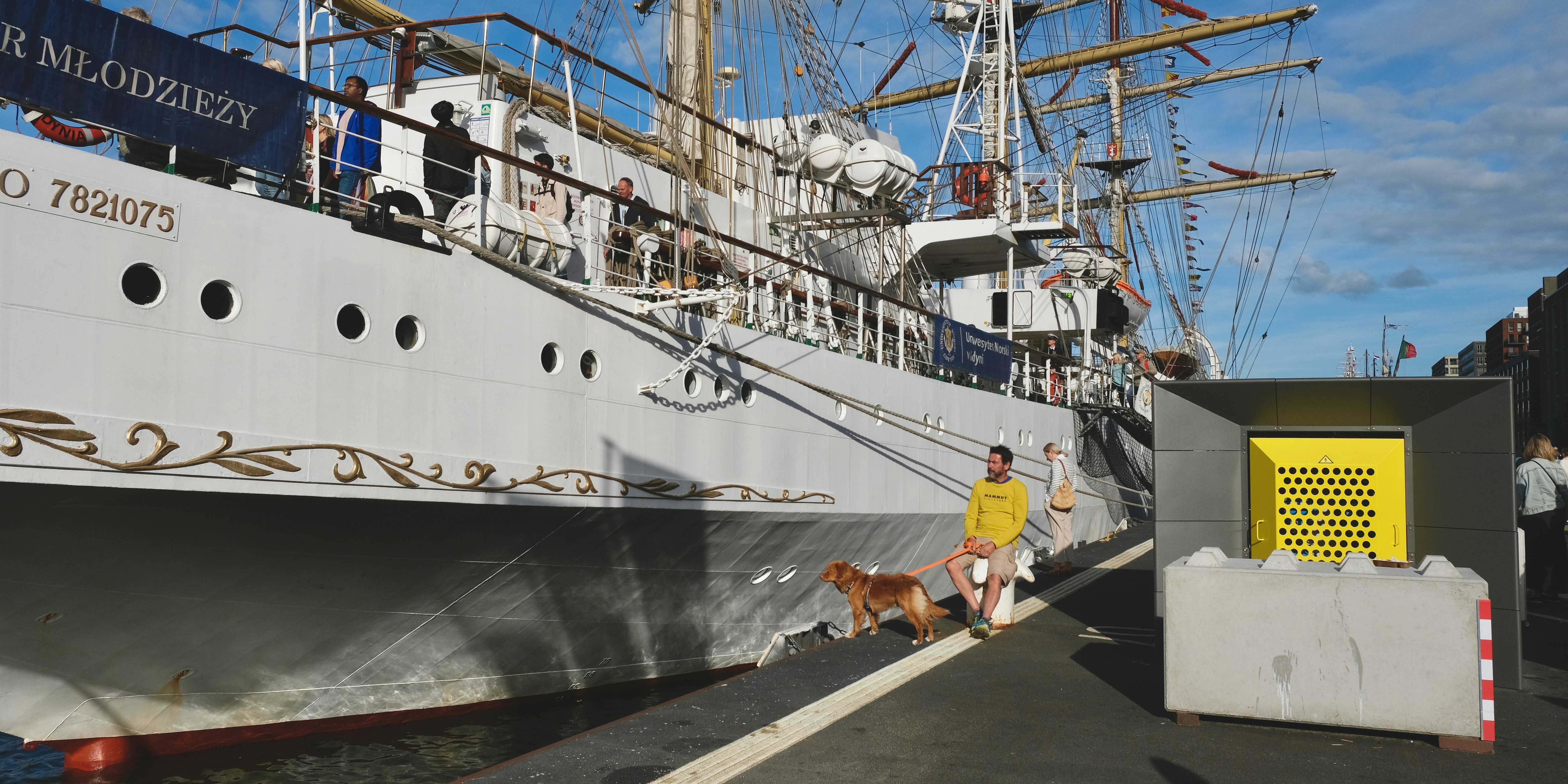 Dockside at Noon: A Historic Vessel, a Dog, and a Concrete Barrier