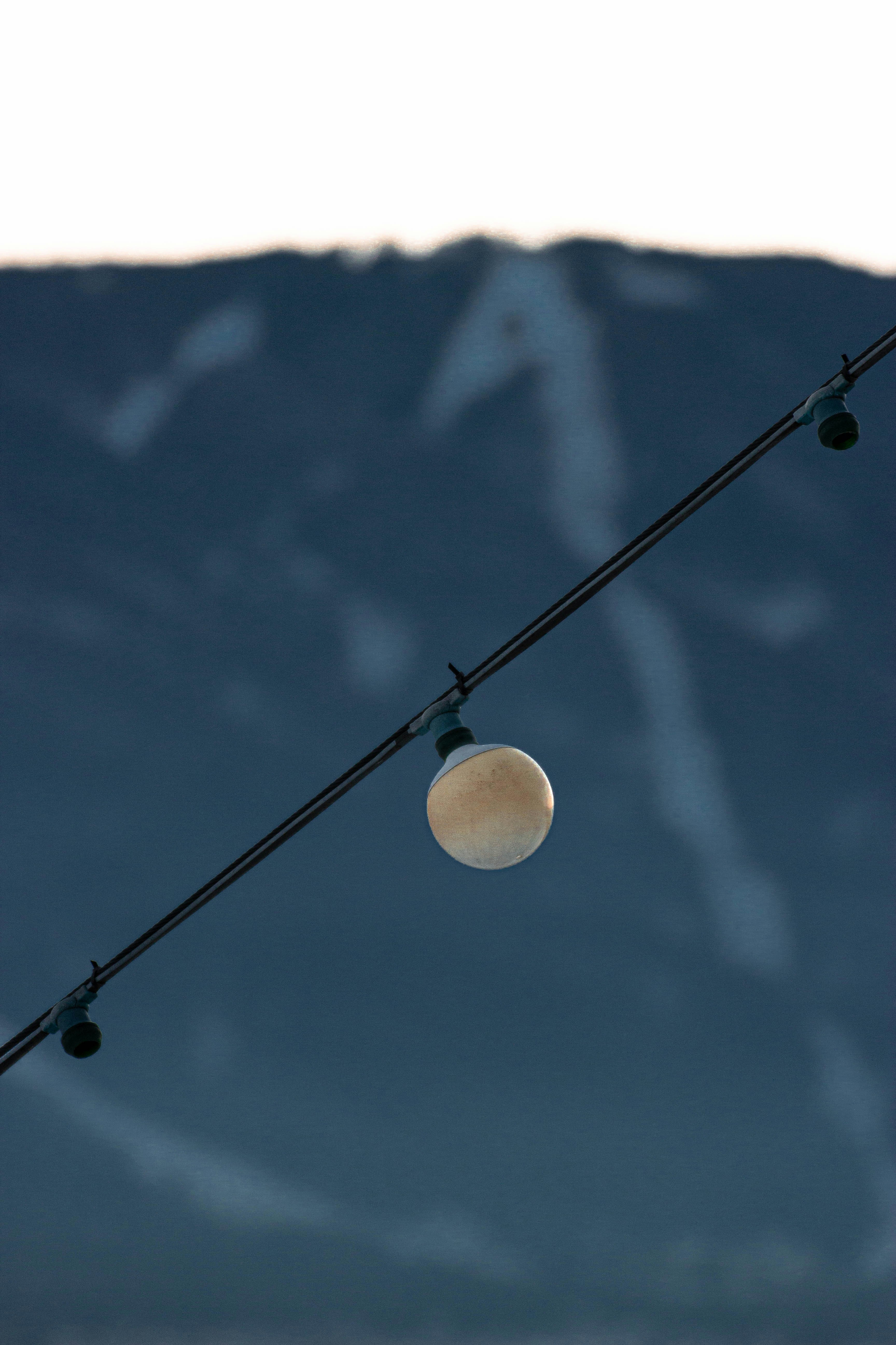 Hanging Light: A Single Bulb Against a Mountain Veil