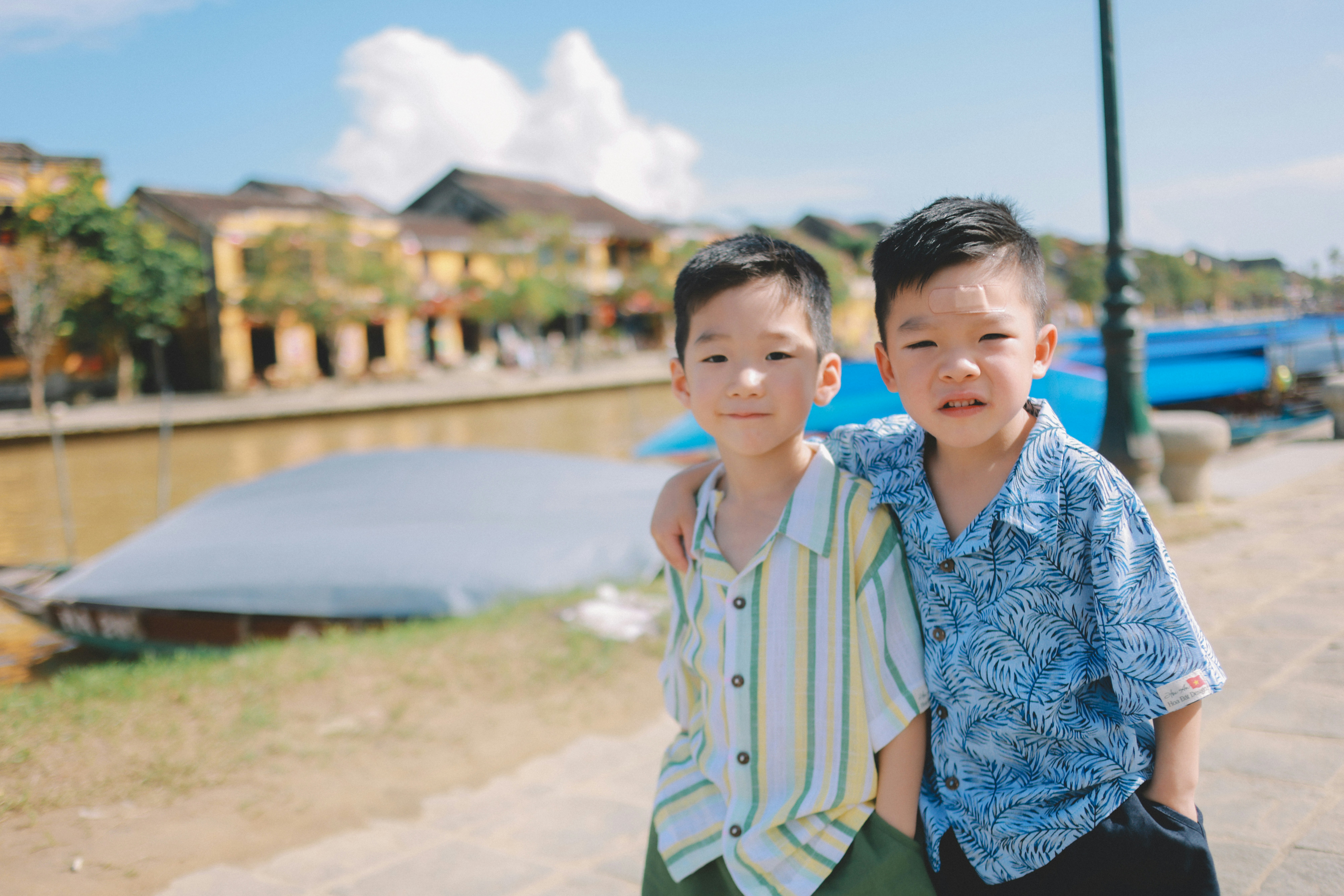 Two brothers by the riverside village under a bright midday sun