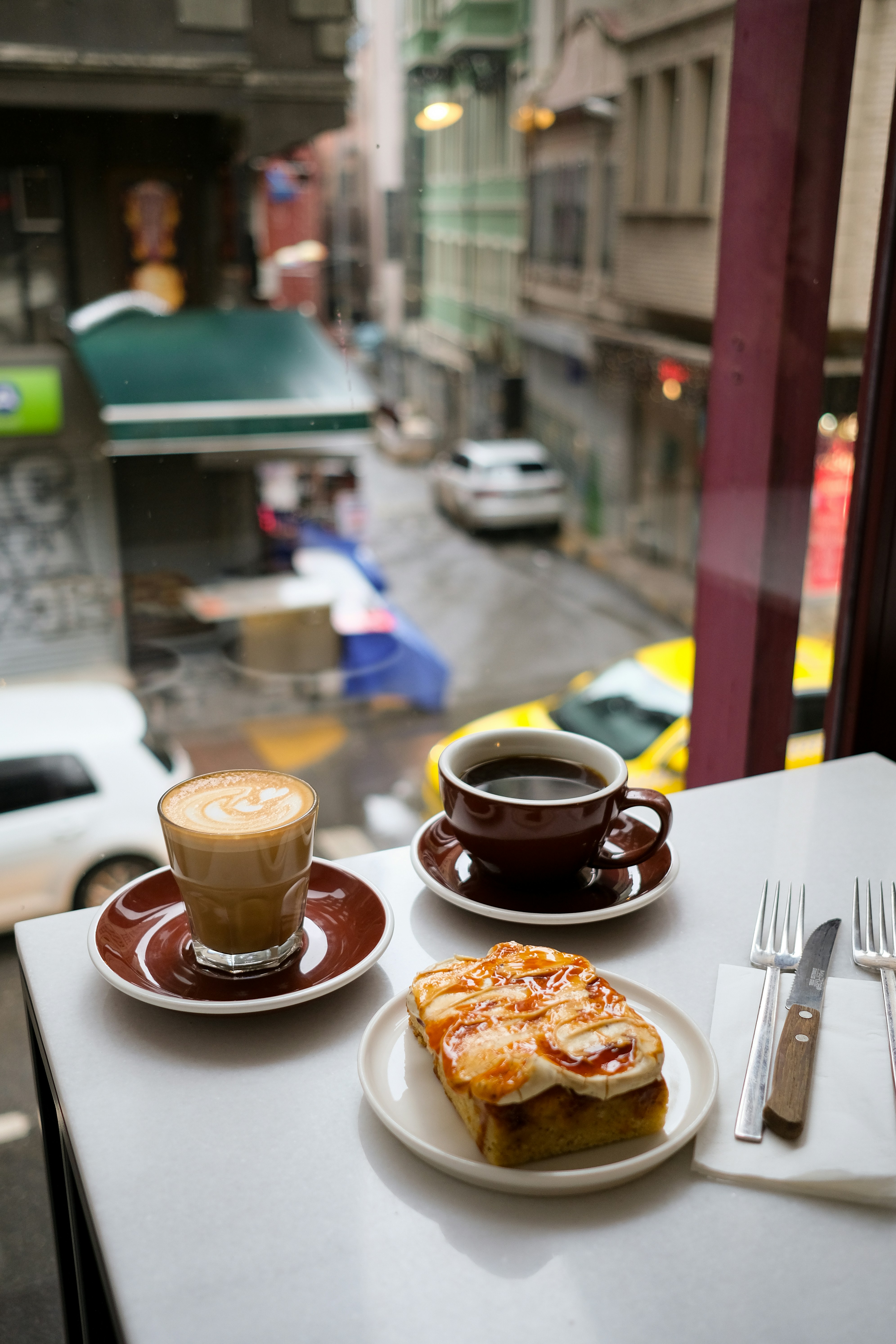 Café Window View: A Slice of Urban Quiet with Coffee and Pastry