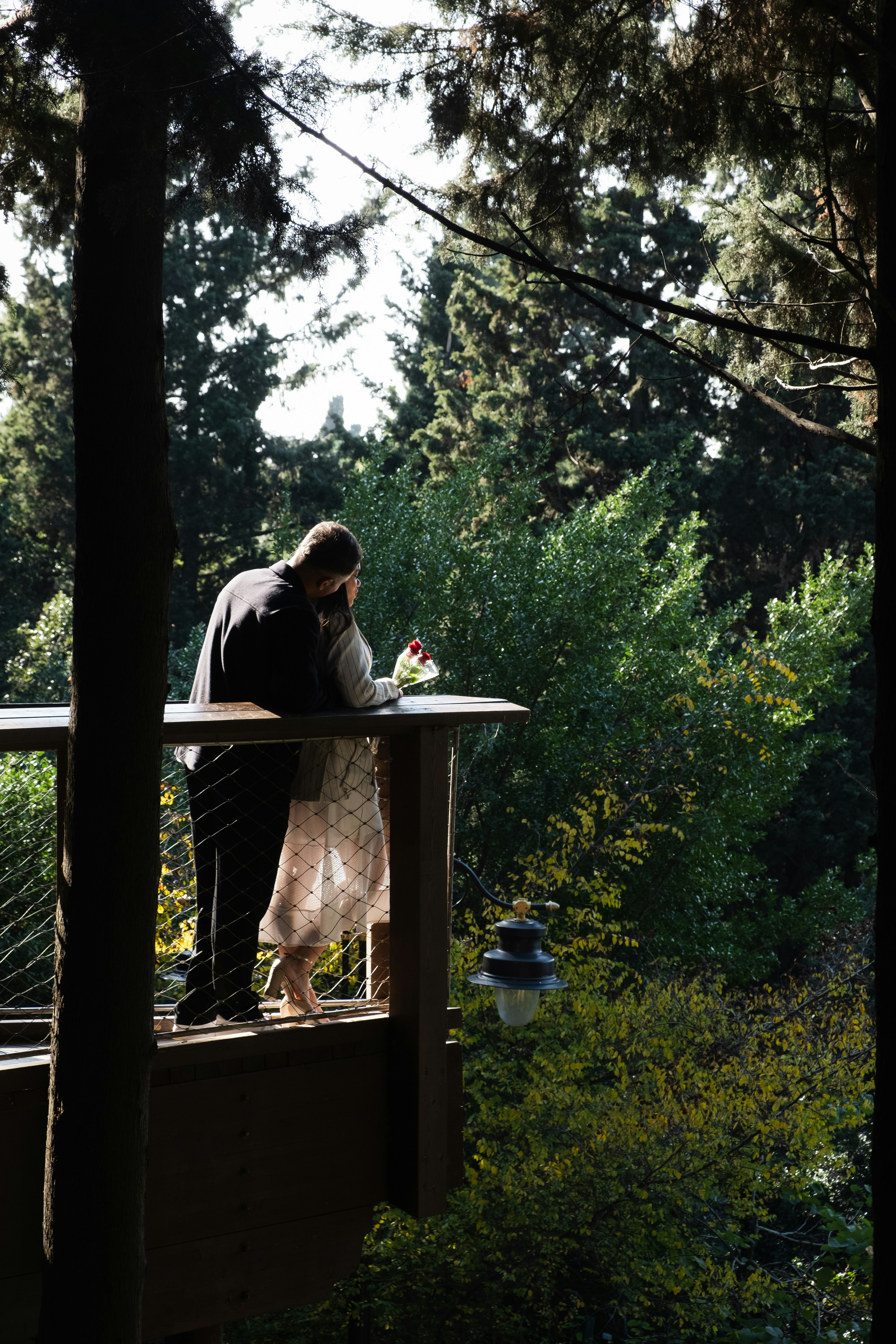 Couple on a wooden balcony sharing a quiet moment amidst a forested overlook