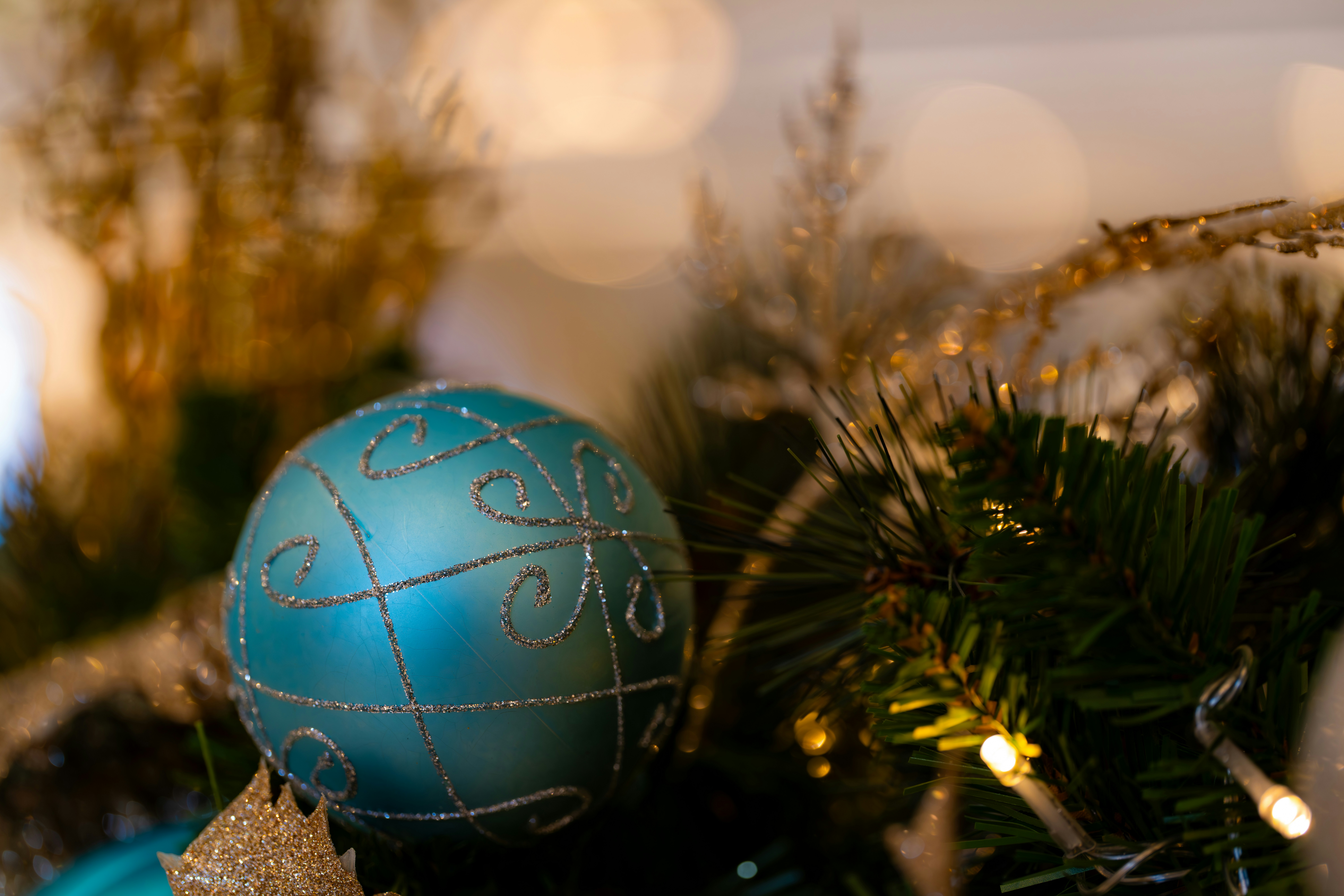 Blue ornament caught in warm festival glow among evergreen boughs