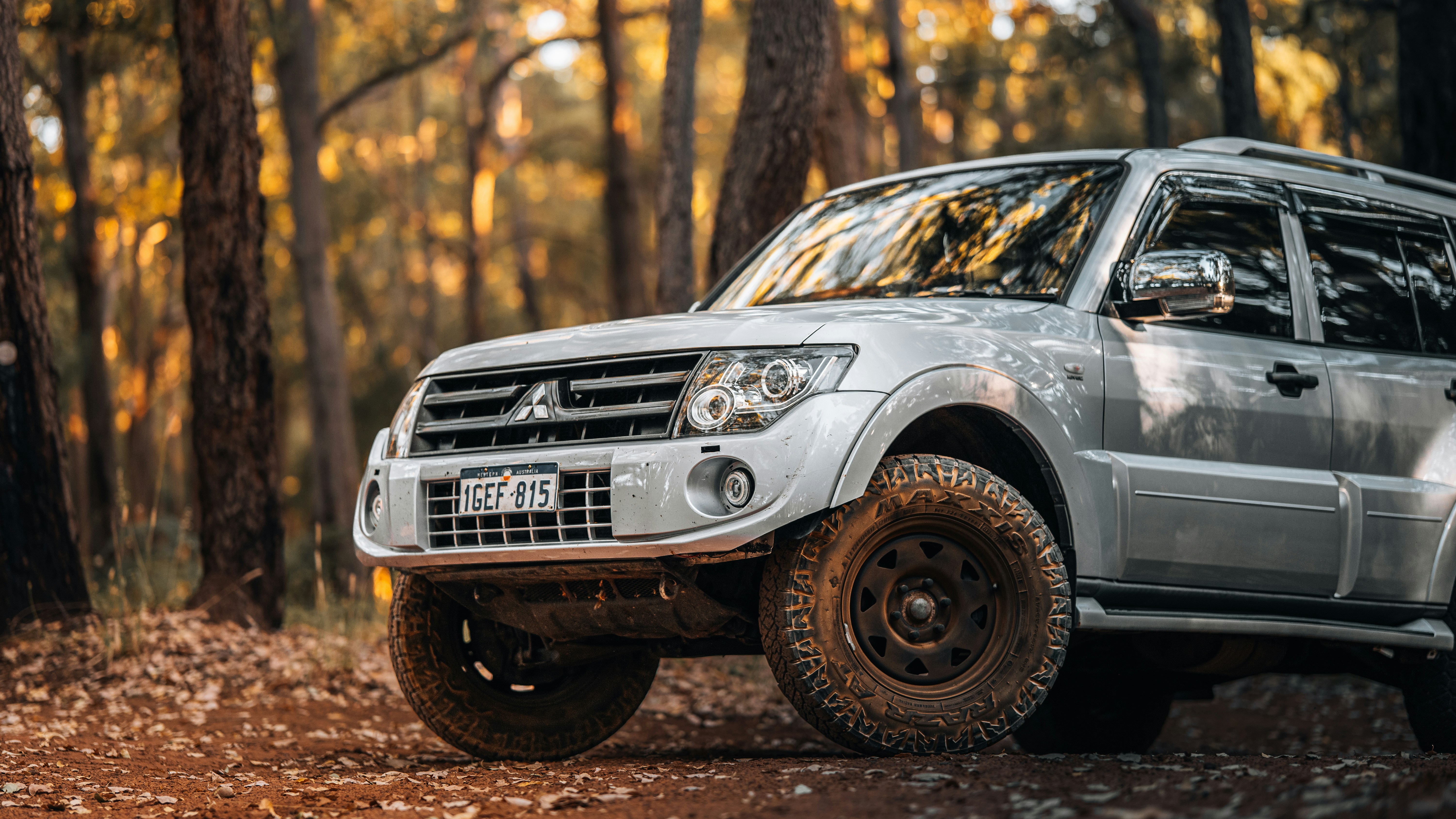 Mud-Splashed Trail King: a rugged SUV held between autumn trees