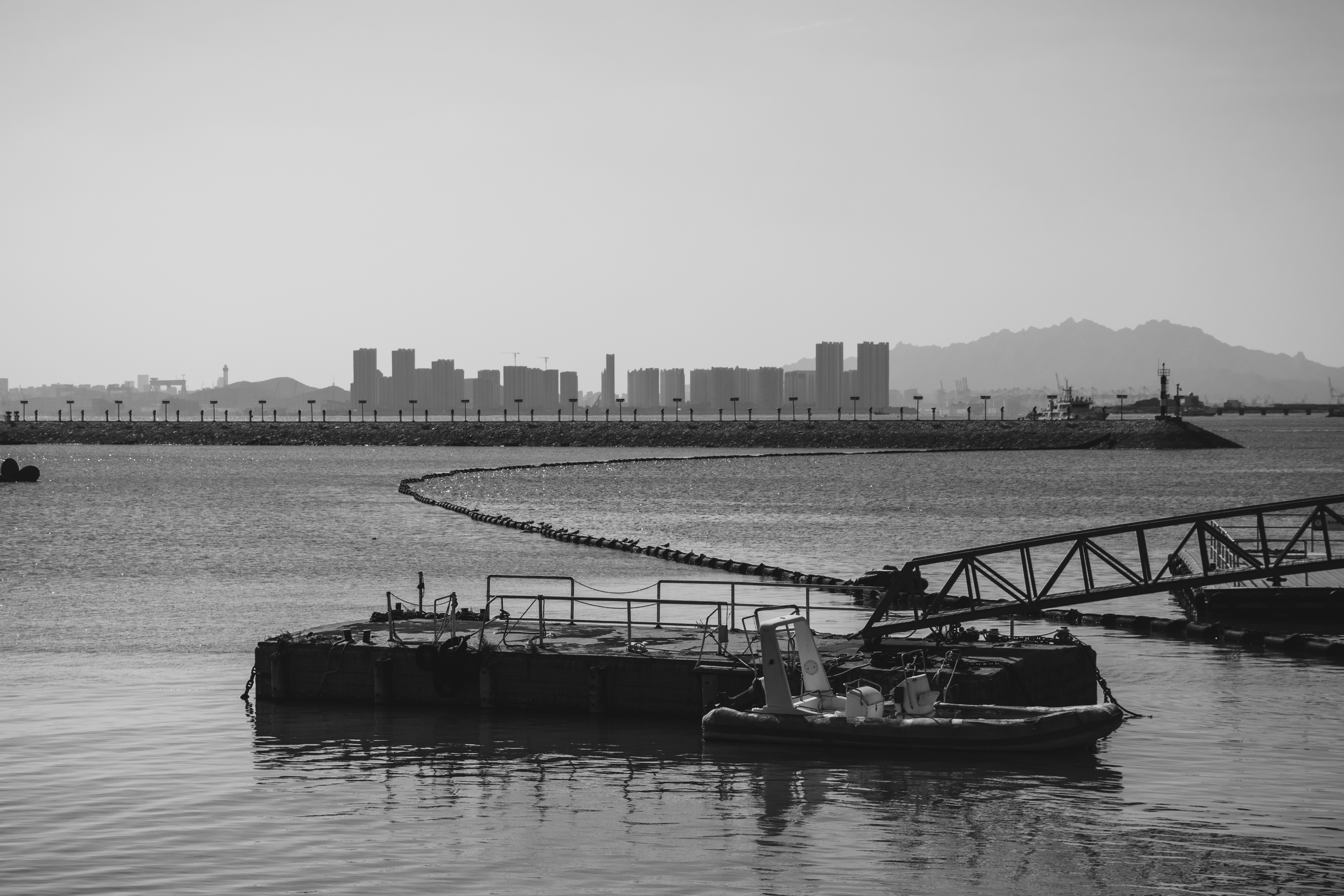 Harbor Barriers: Boats and Breakwater Fringes Under Distant City Lights